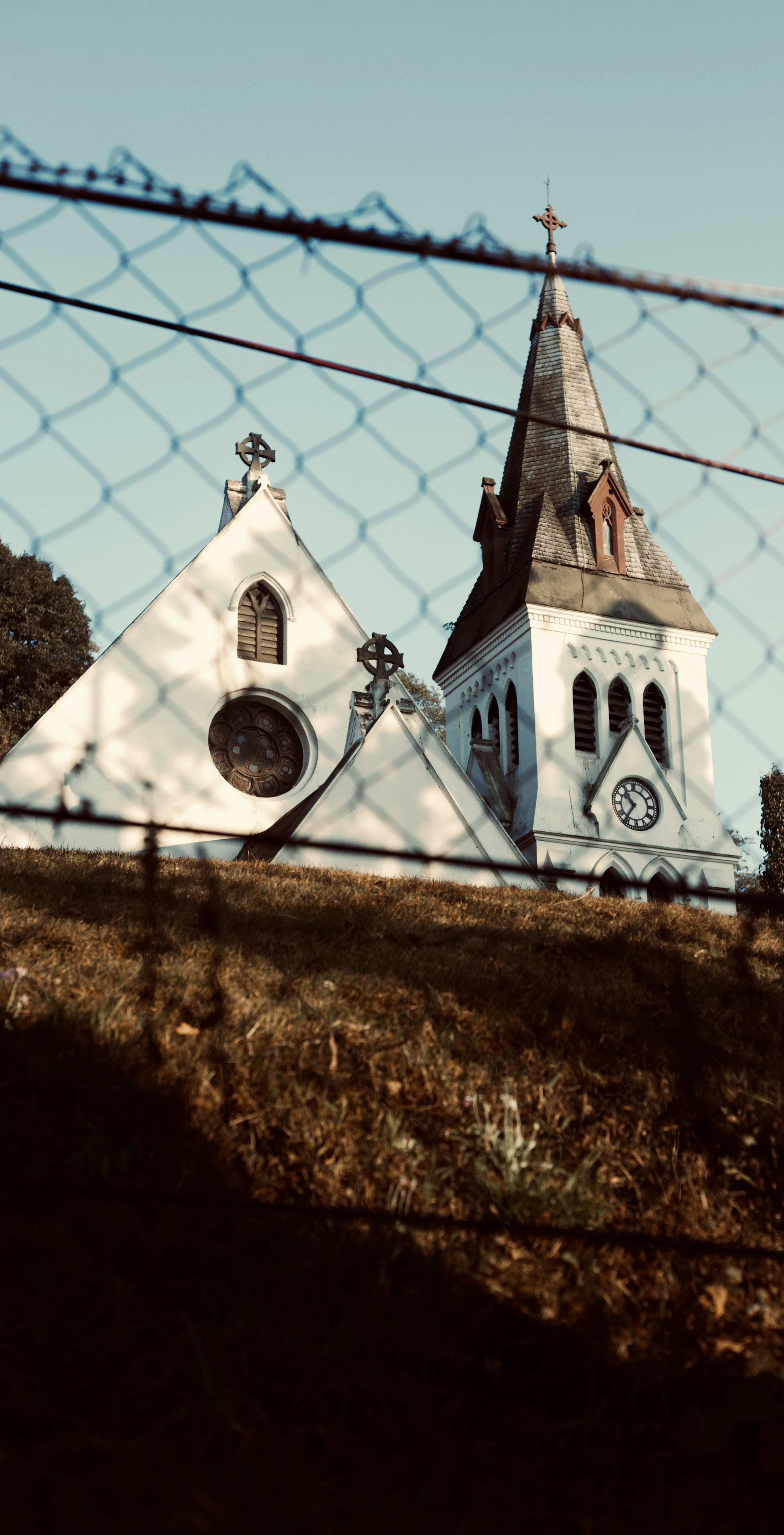 Charmed Chapel Behind Chain-Link: A Sunlit White Church Reaching Toward the Sky