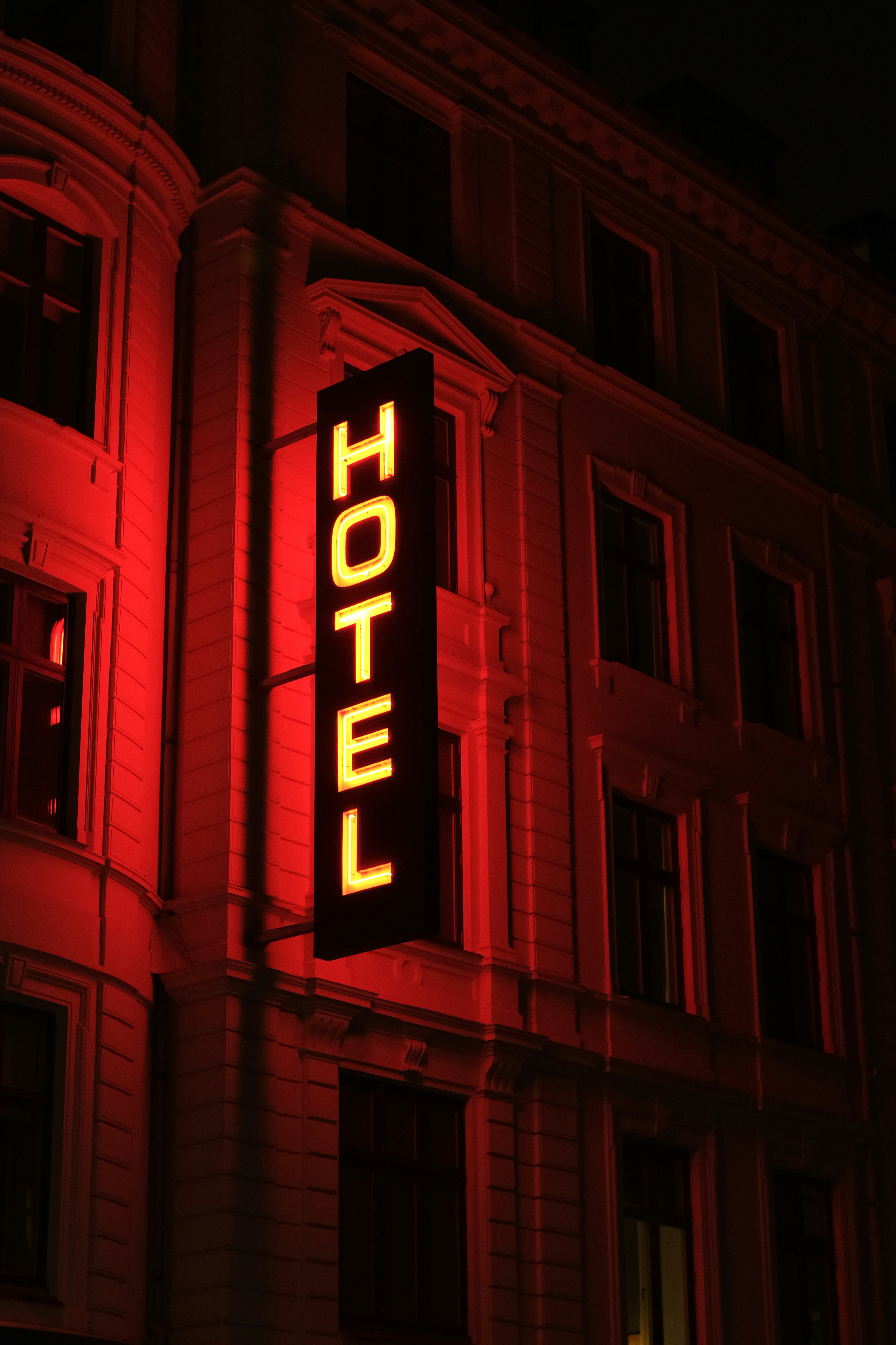 A hotel sign lit up at night in front of a building photo – Free ...