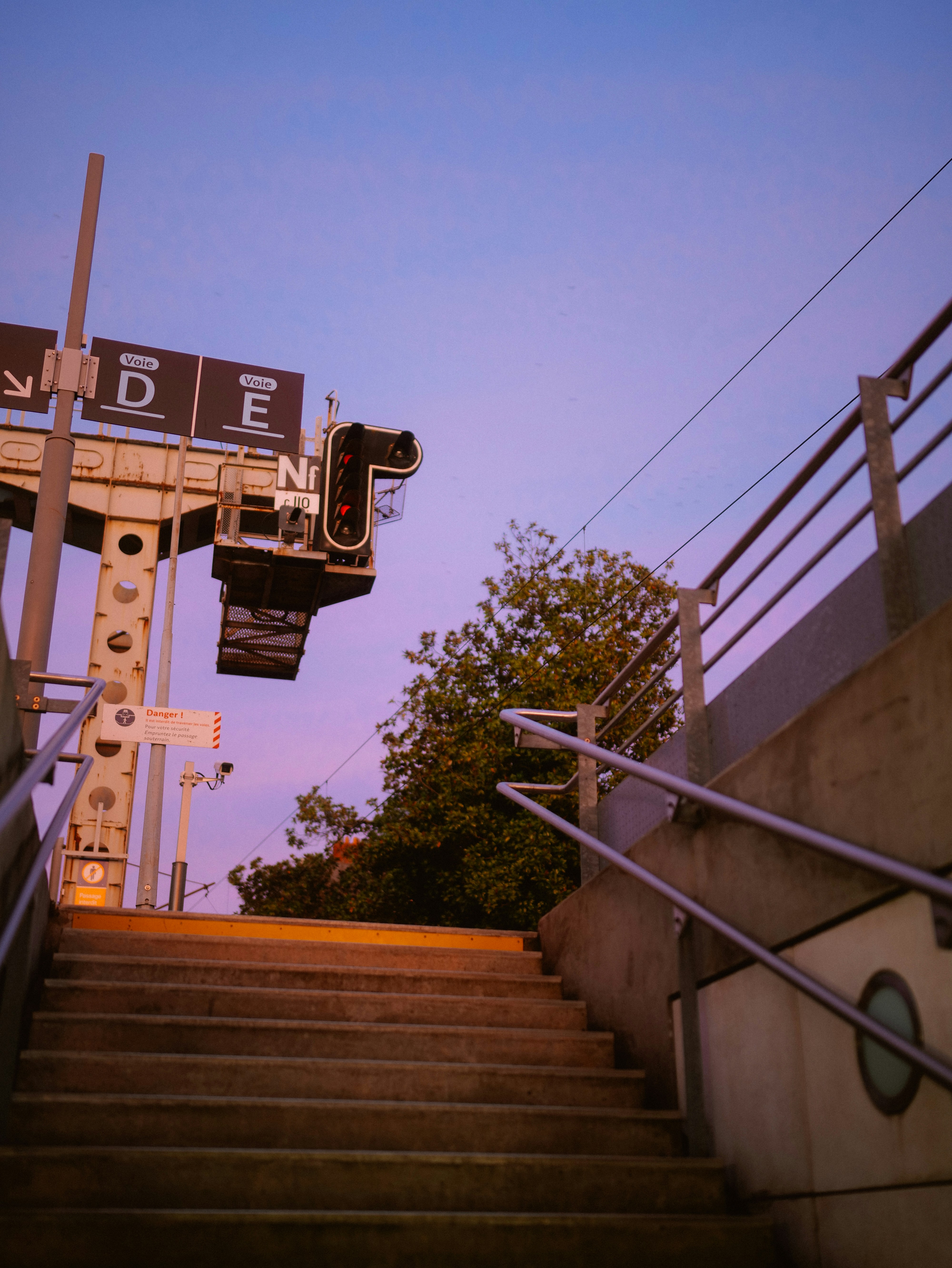 Twilight Ascent to the D/E Platform: A Concrete Staircase Framed by Rails and a Signaling Beacon