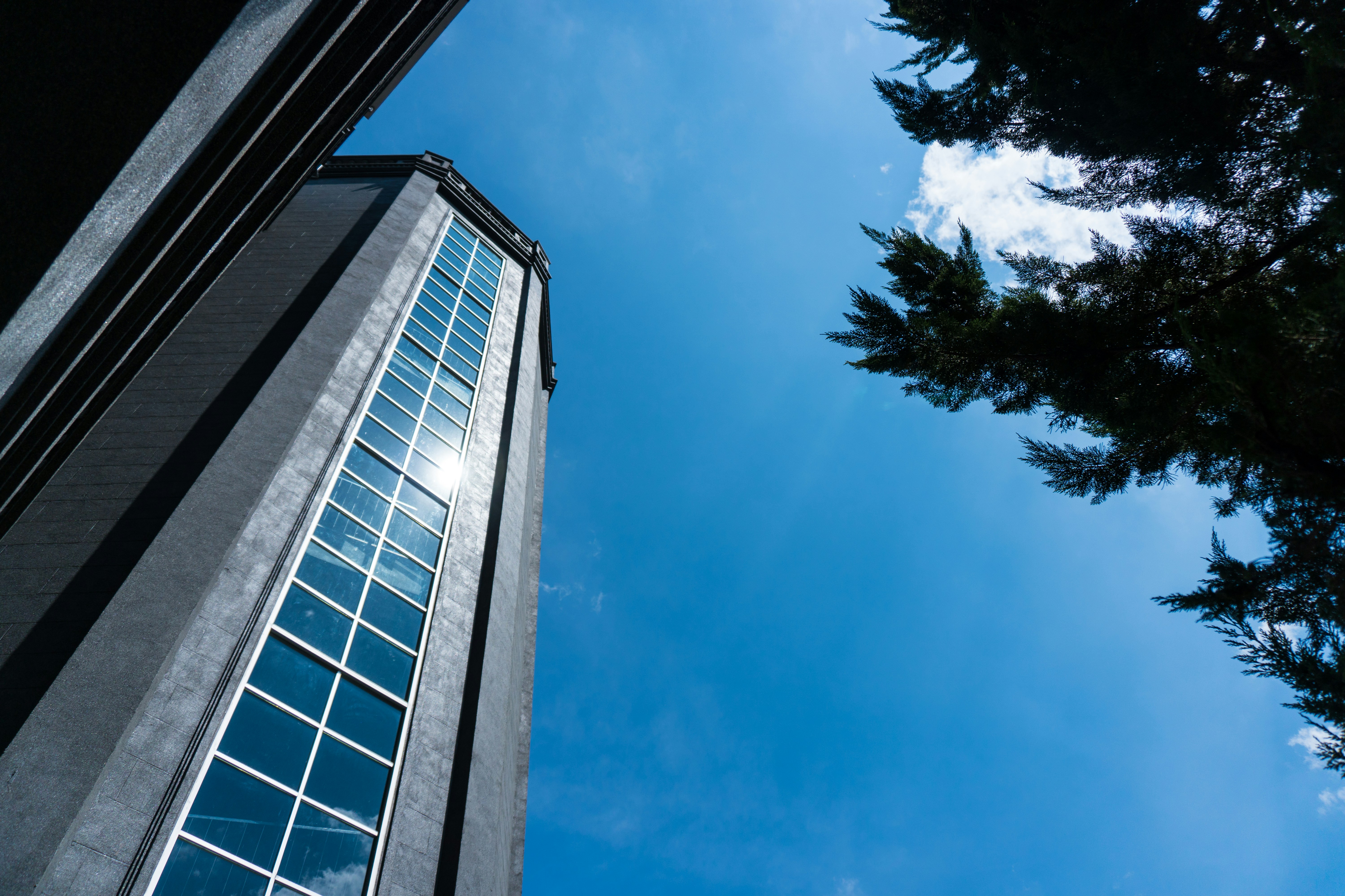 Leaning Glass Facade Reaching Toward a Clear Blue Sky