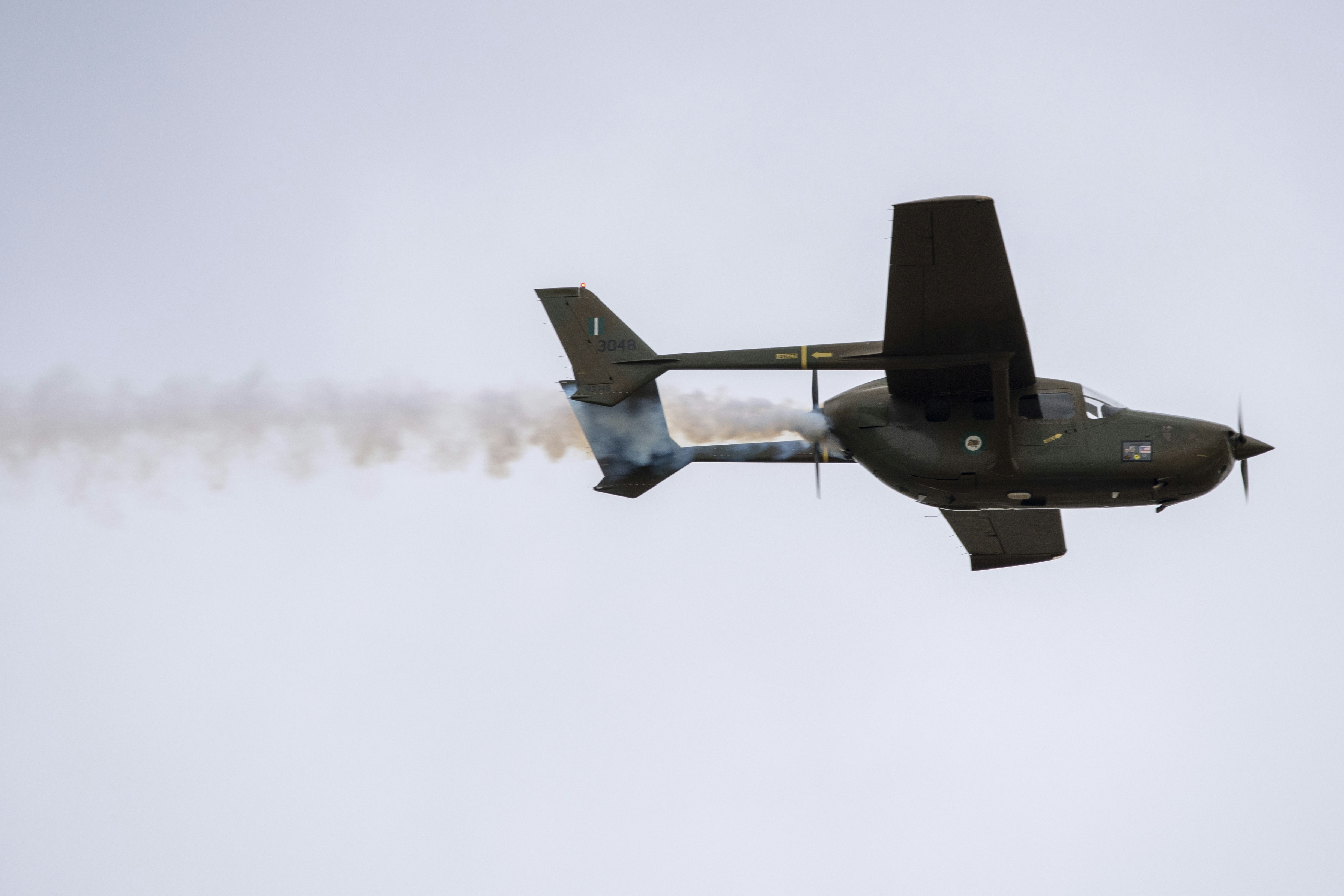 Contrail Scout: A Green Tactical Aircraft Cuts Through a Pale Sky