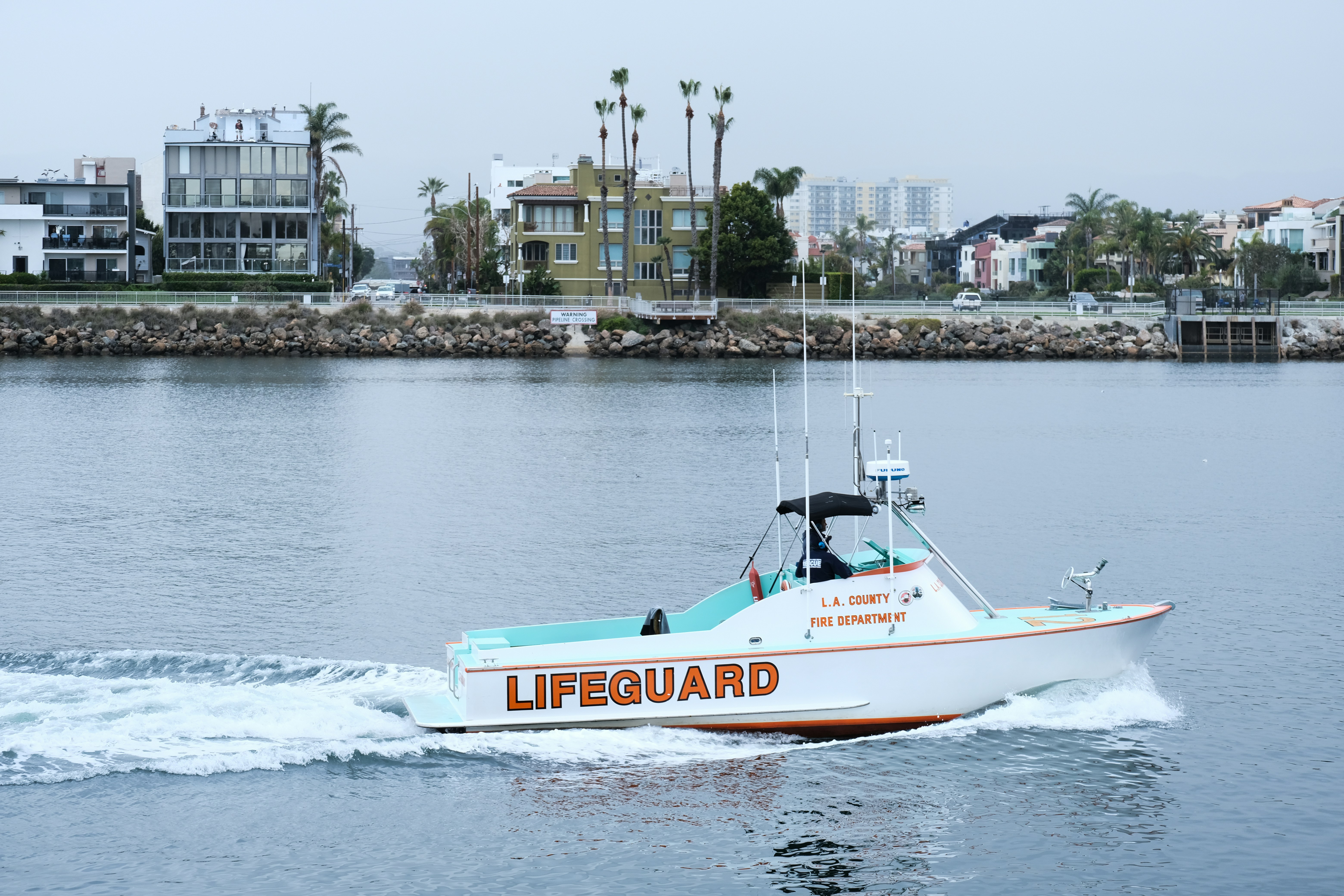 A lifeguard boat in the water with palm trees in the background photo ...