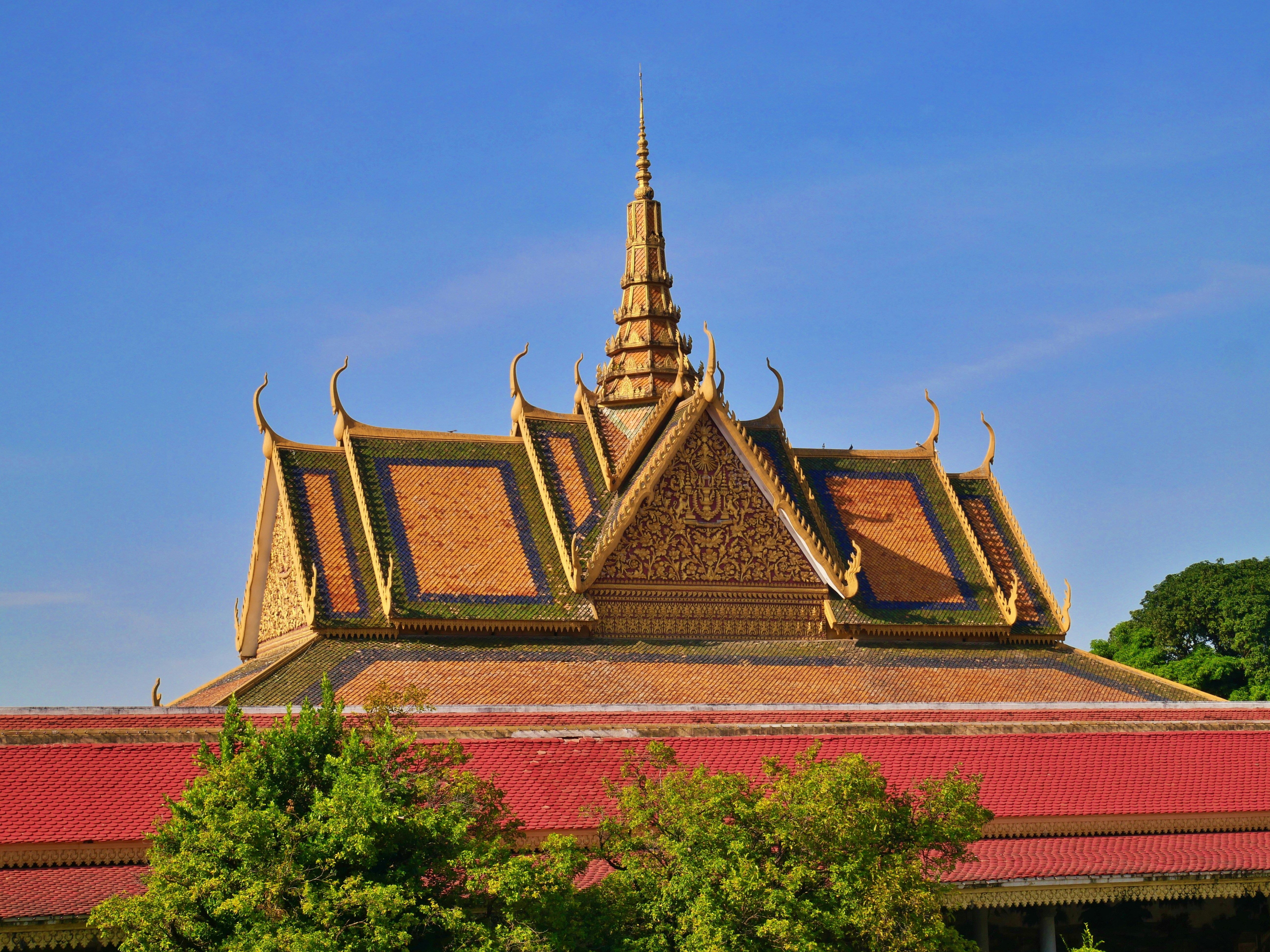 Ornate temple roof with golden spires against a clear blue sky.
