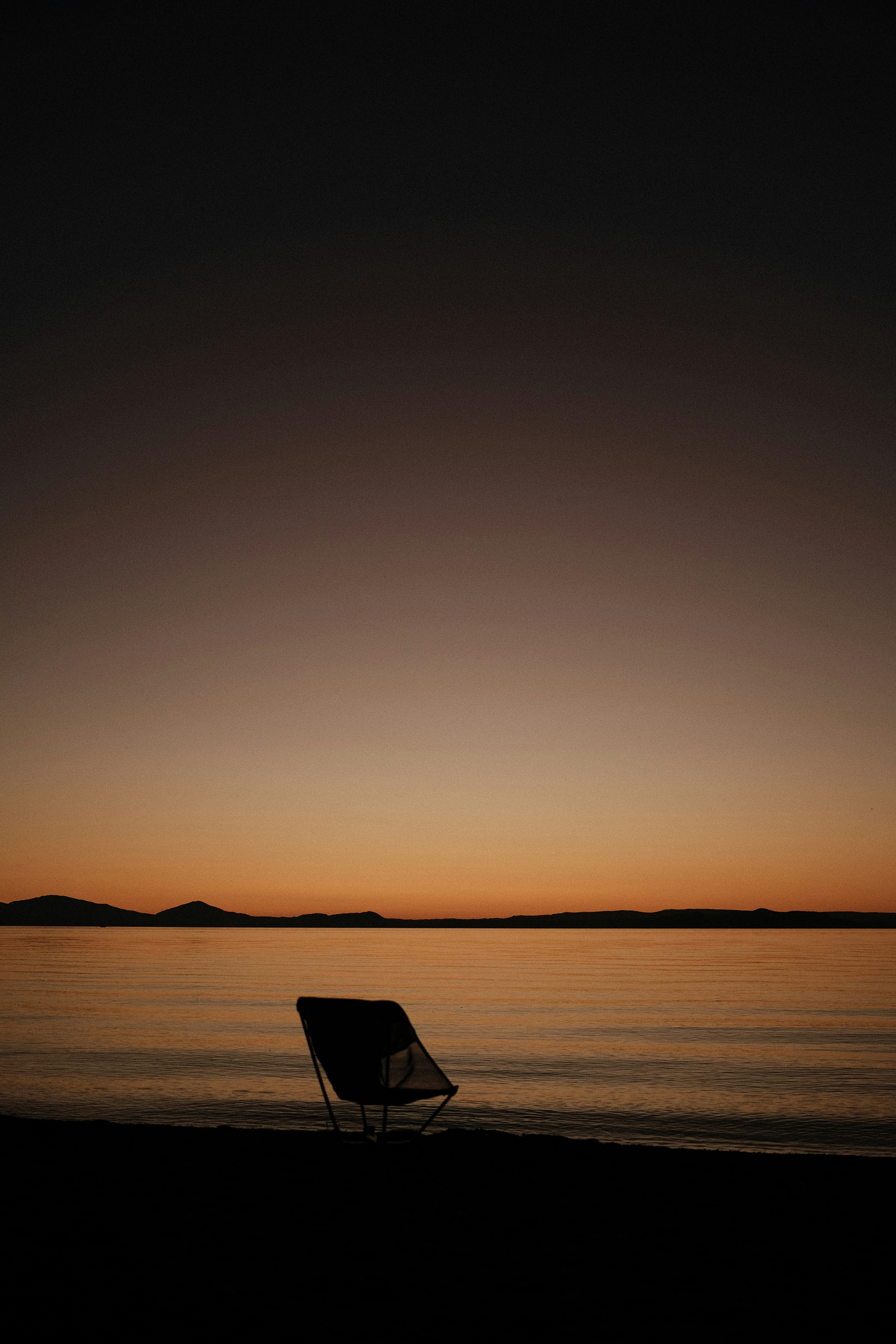 a chair sitting on top of a beach next to the ocean
