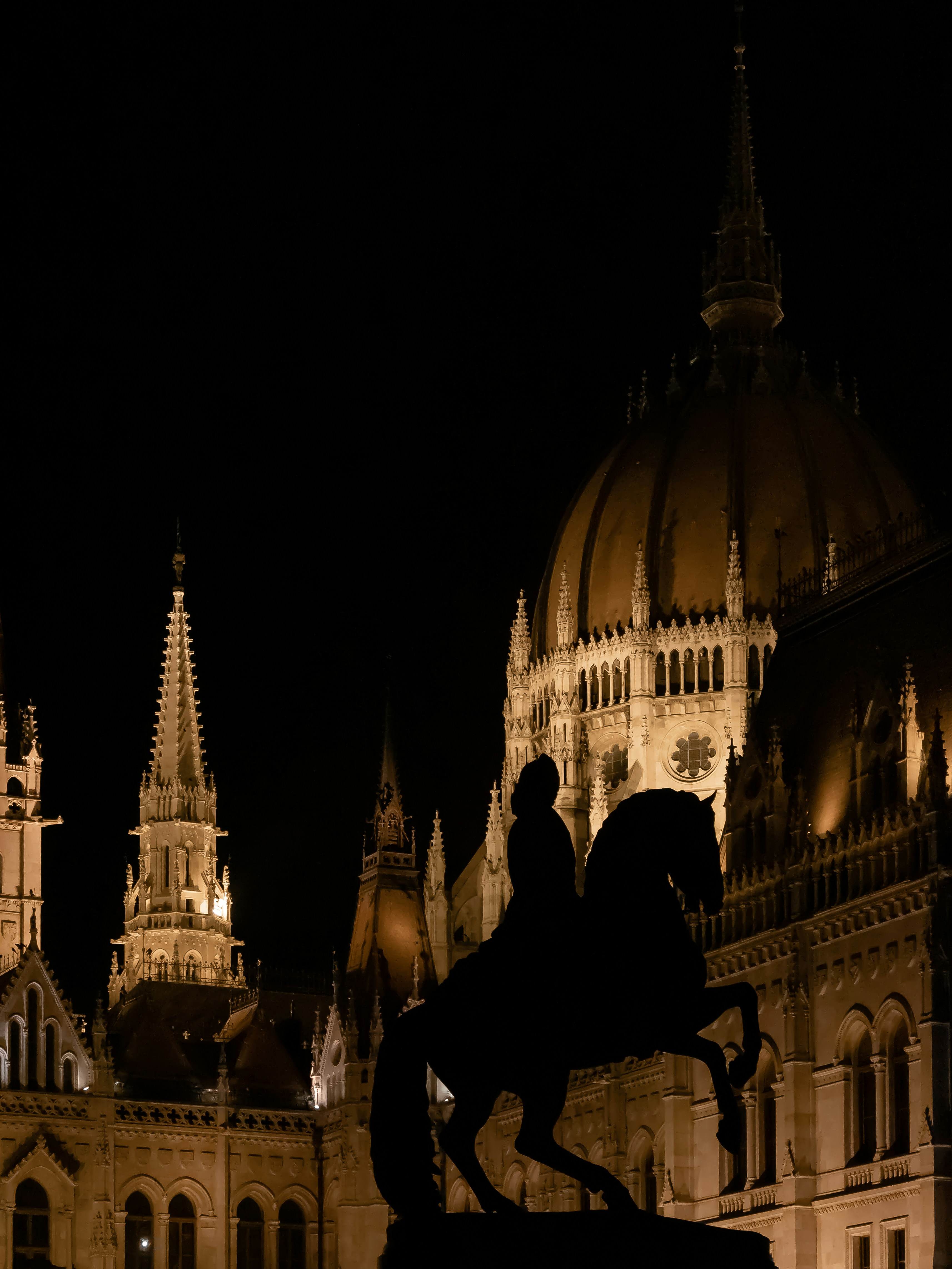 Midnight Silhouette: A Horse Statue Framed by Budapest's Illuminated Parliament Dome