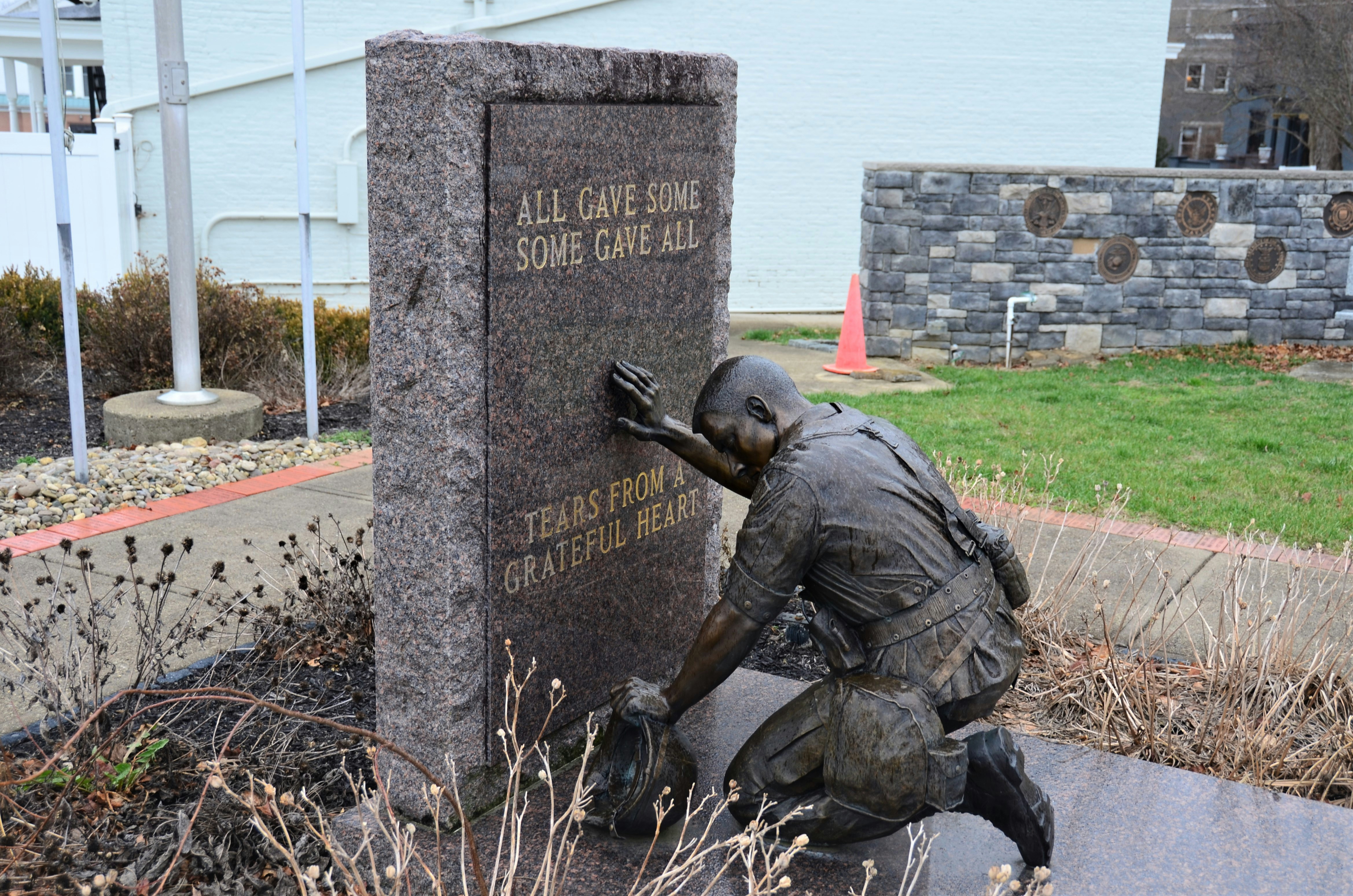 A statue of a man kneeling next to a monument photo – Free Building ...