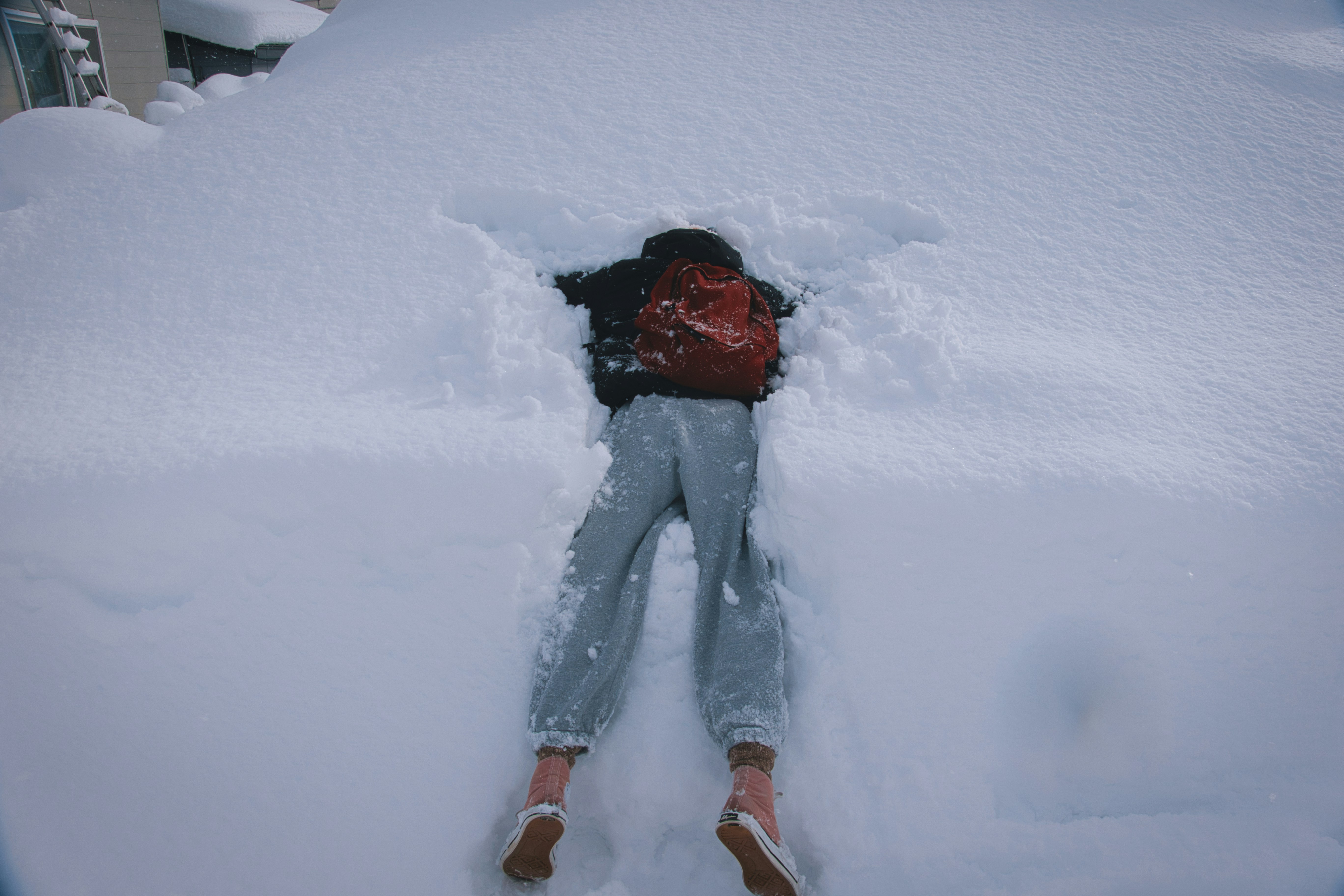 a person laying in the snow with a backpack on their back photo – Free ...