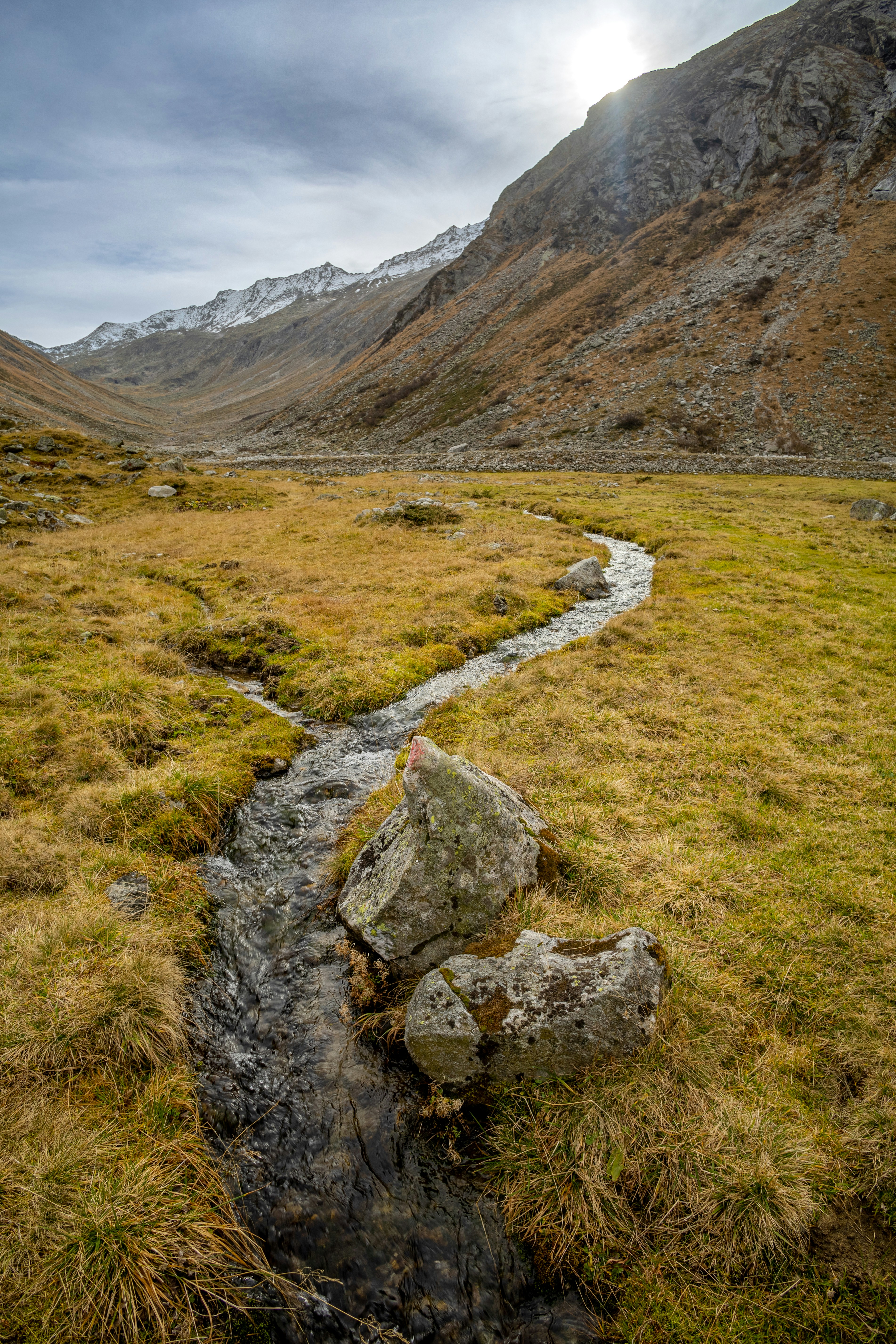 a stream running through a grass covered valley