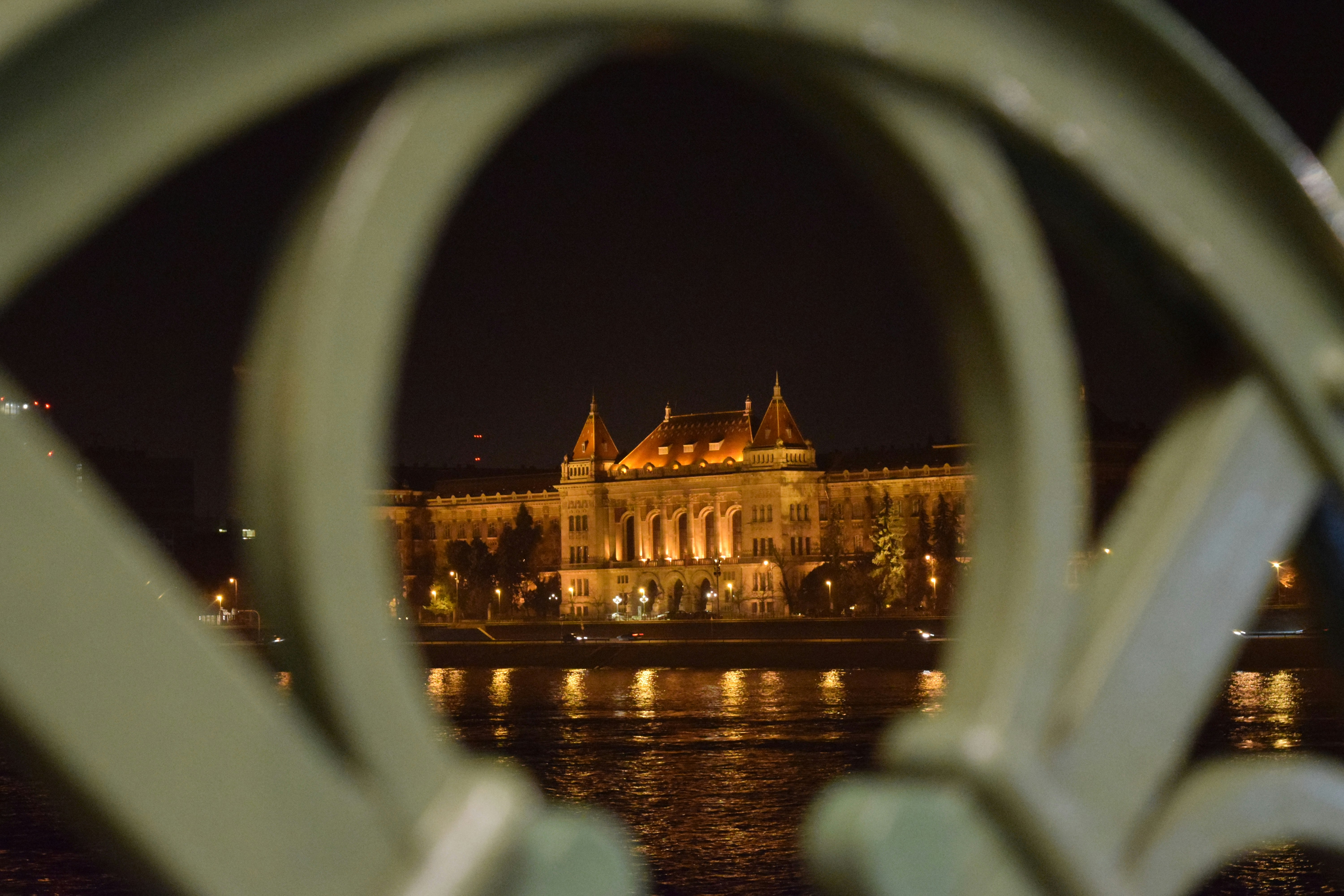 Through a Circular Frame: Night-Lit Riverside Palace Framed by Iron Rings