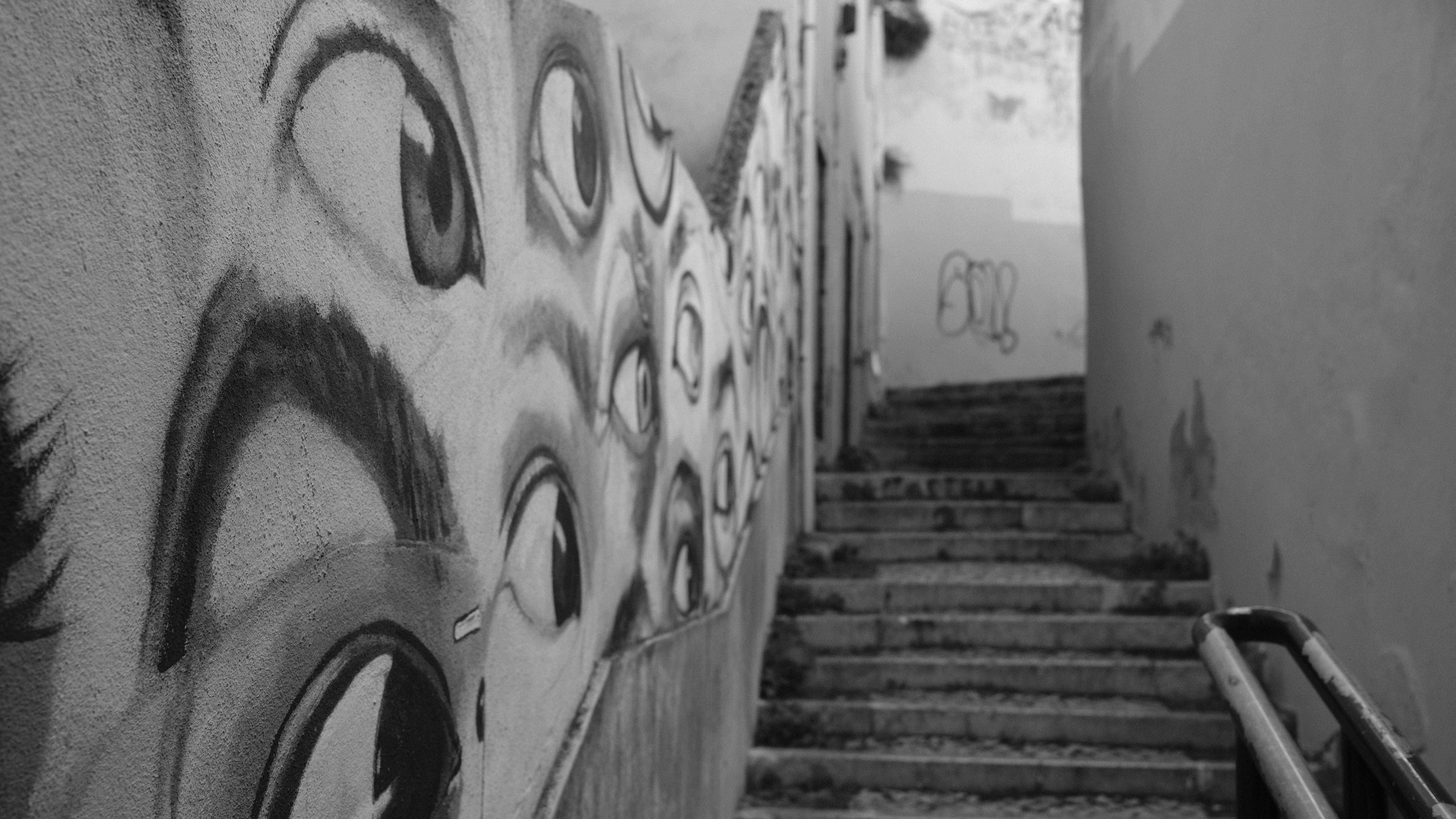 Echoes in the Stairwell: Graffiti Faces Lead the Descent