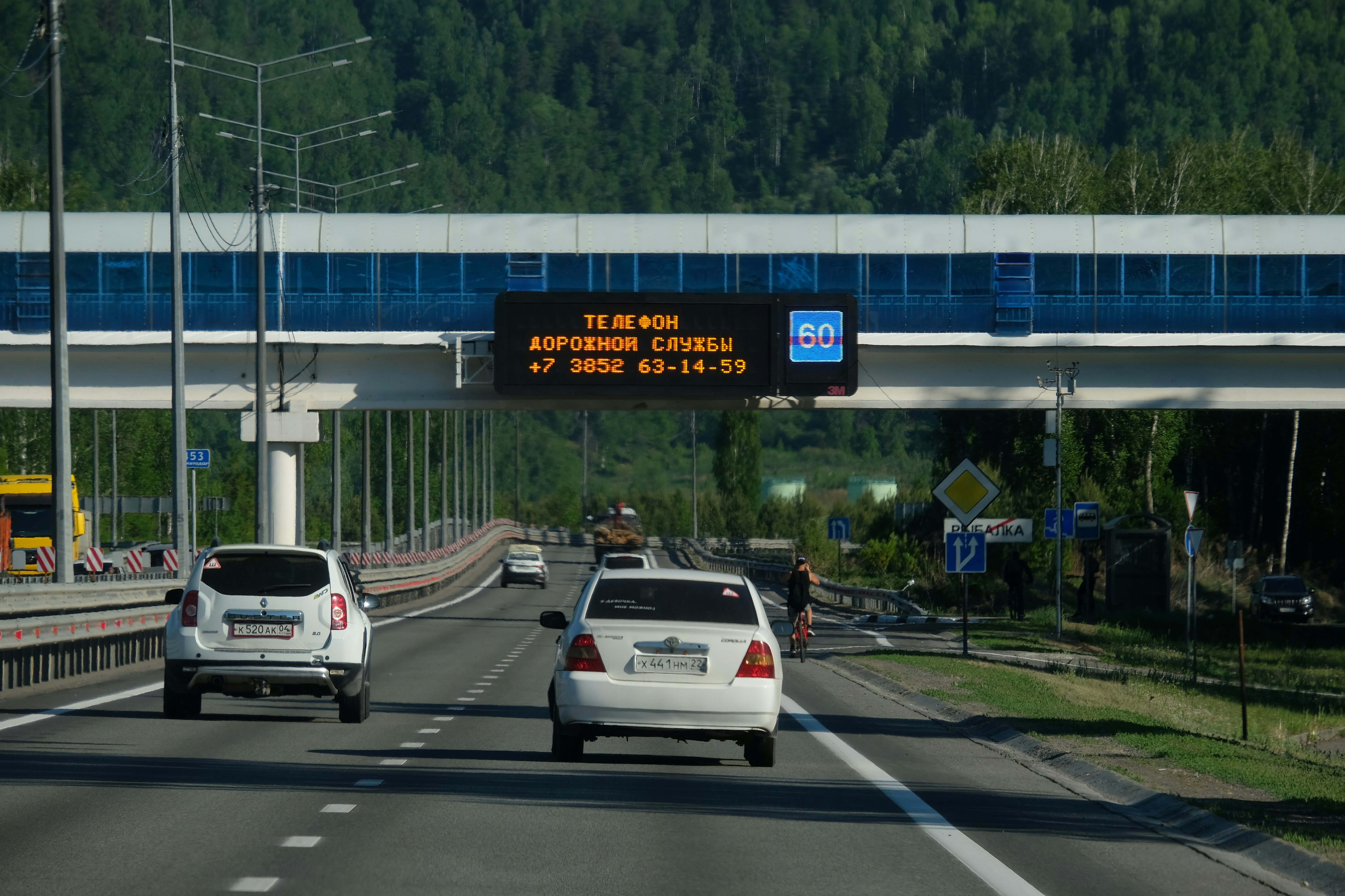 Two cars driving down a highway under a bridge photo – Free Car Image ...