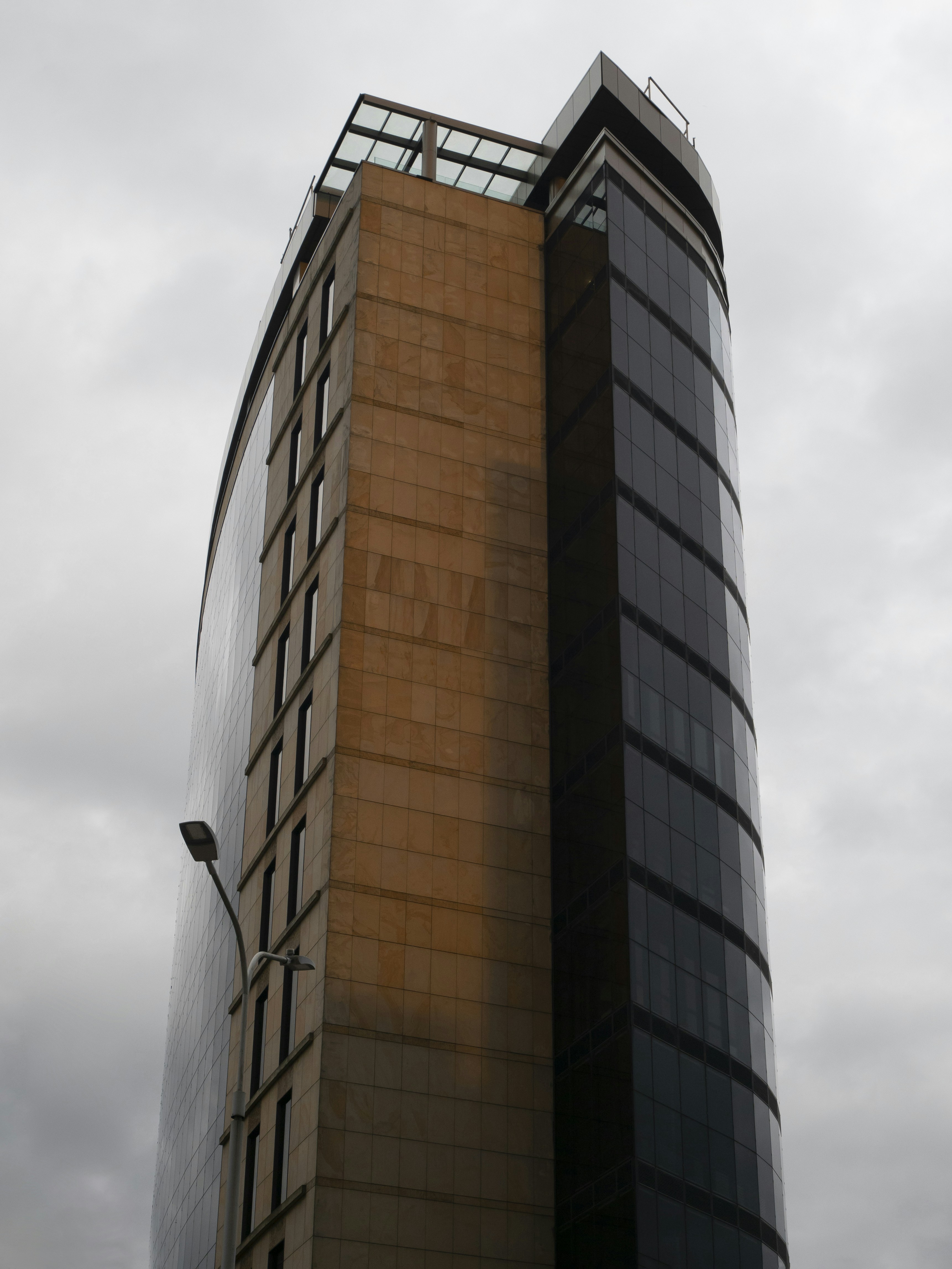 Glass and Stone: A Slim Tower Reaching into an Overcast Sky