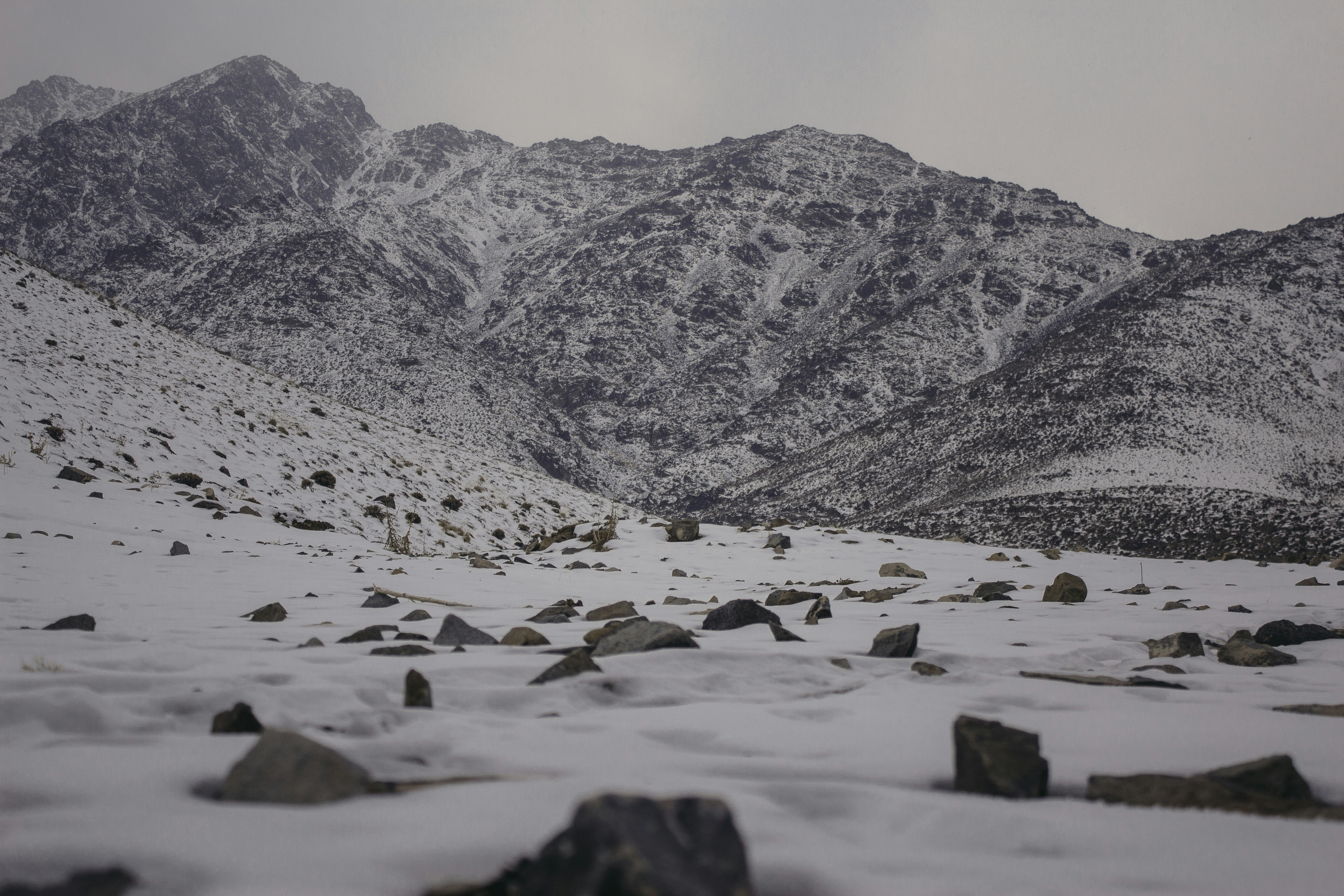 A snow covered mountain range with rocks and boulders photo – Free Snow ...