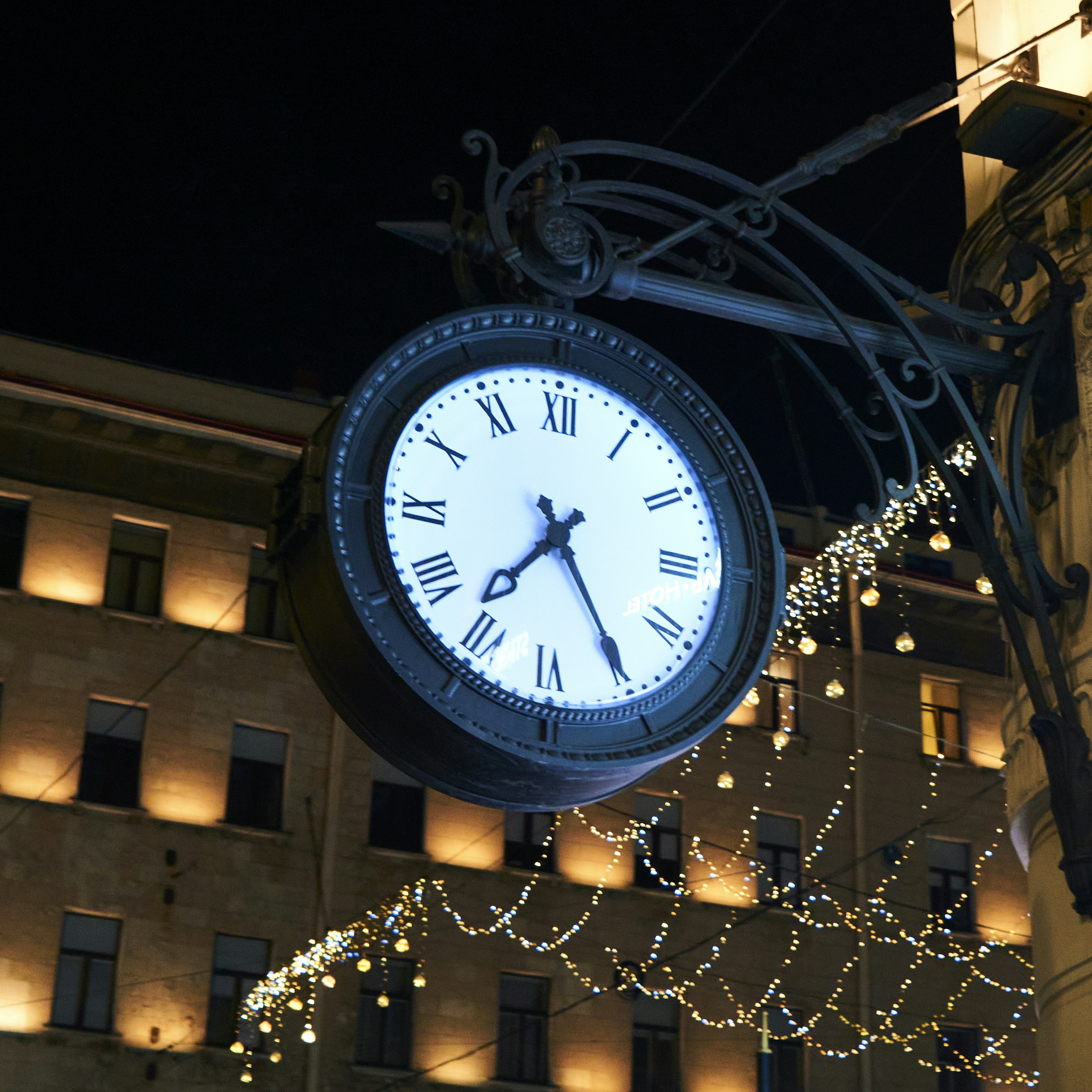 Ornate Street Clock Beneath a Veil of Holiday Lights