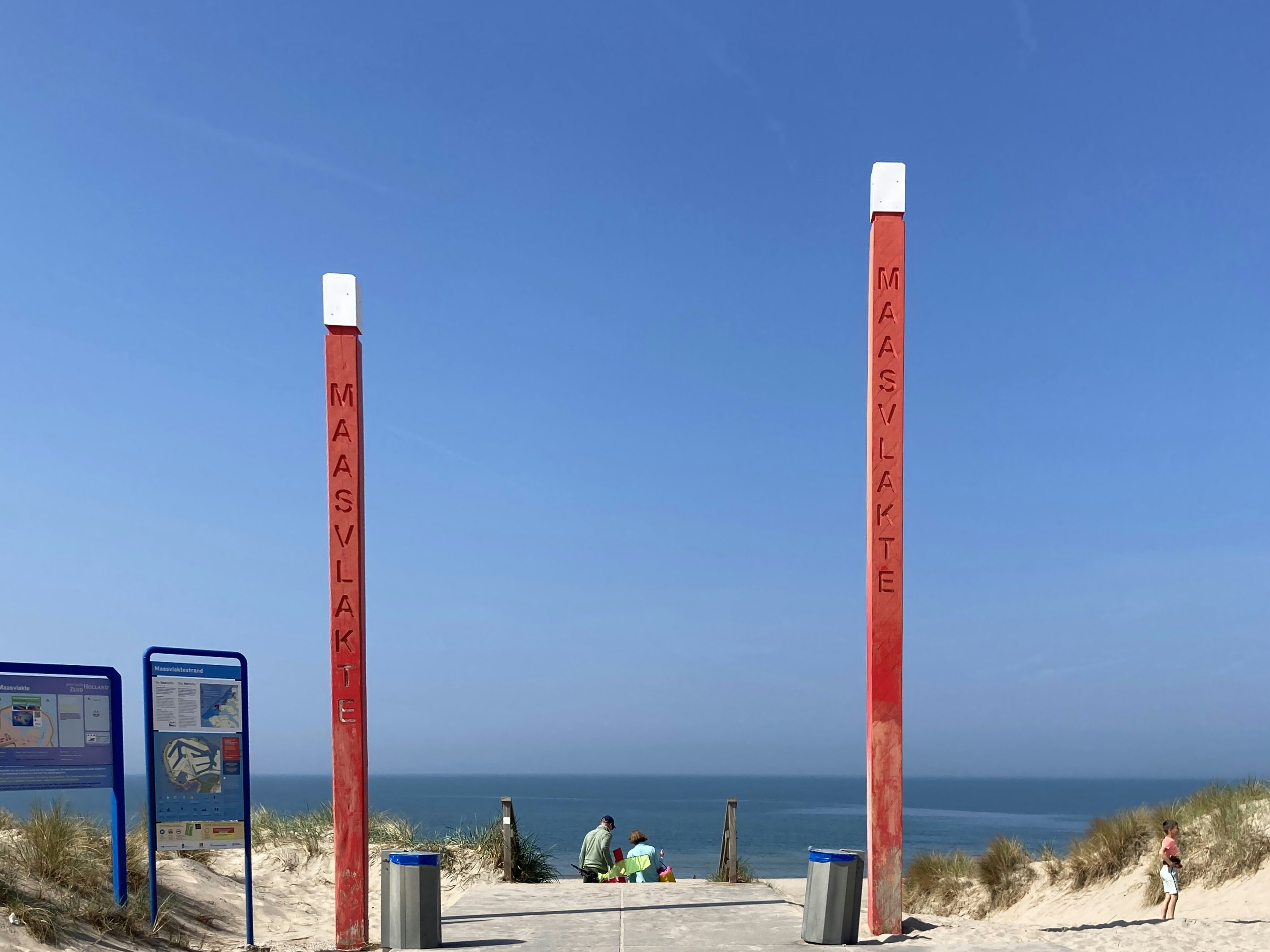 A couple of tall red poles sitting on top of a sandy beach photo – Free ...