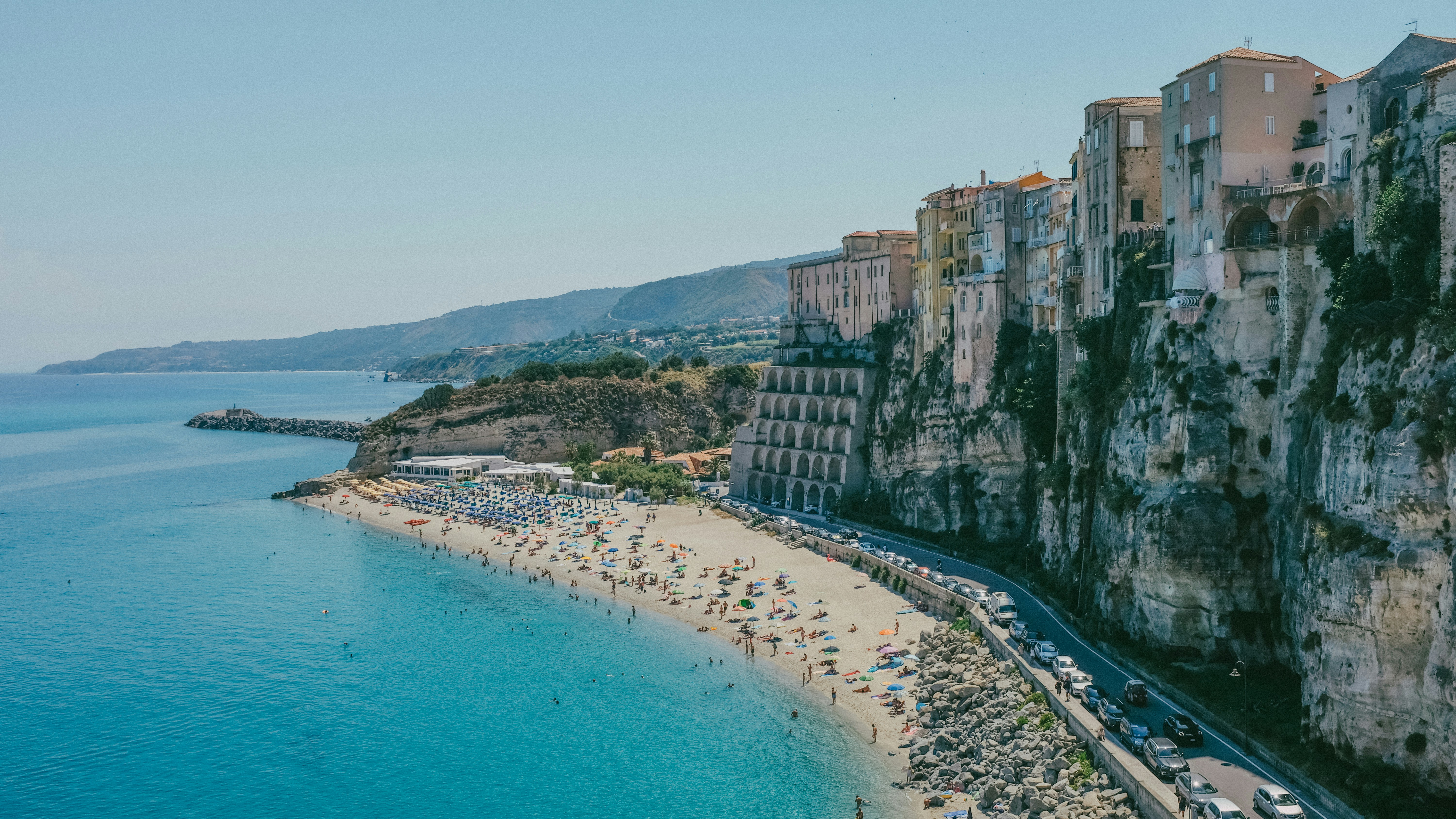 A beach next to a cliff with people on it photo – Free Image on Unsplash