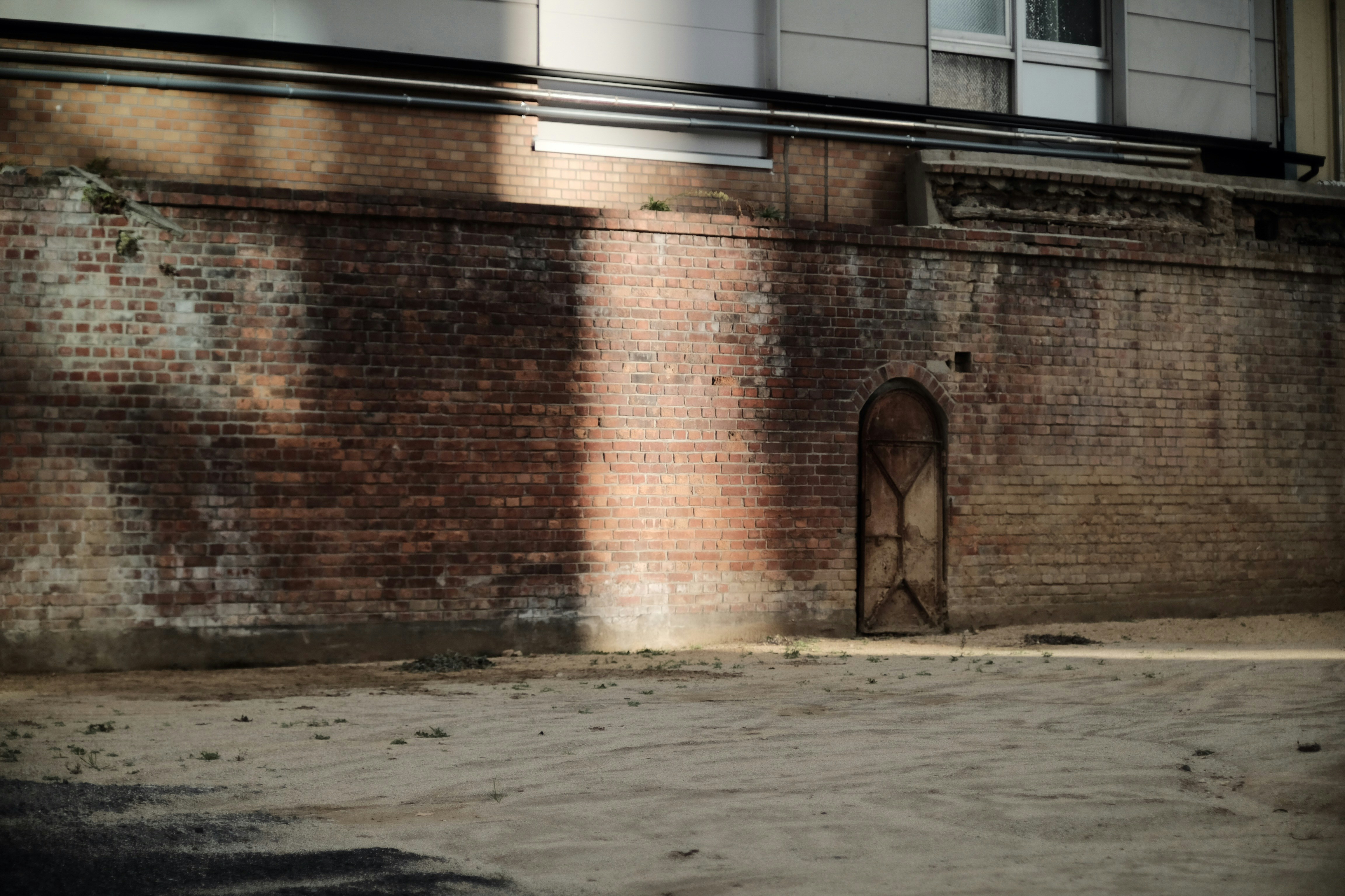 Sunlit Brick Wall and Iron Door: Quiet Urban Boundary