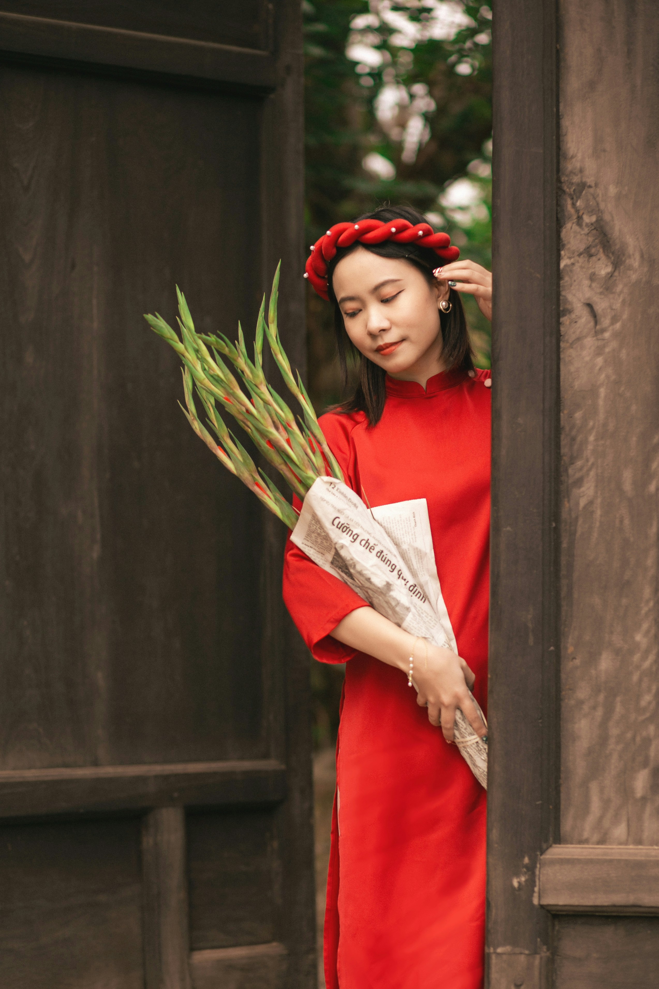 Crimson Silk at the Threshold: A Poised Portrait in a Wooden Doorway
