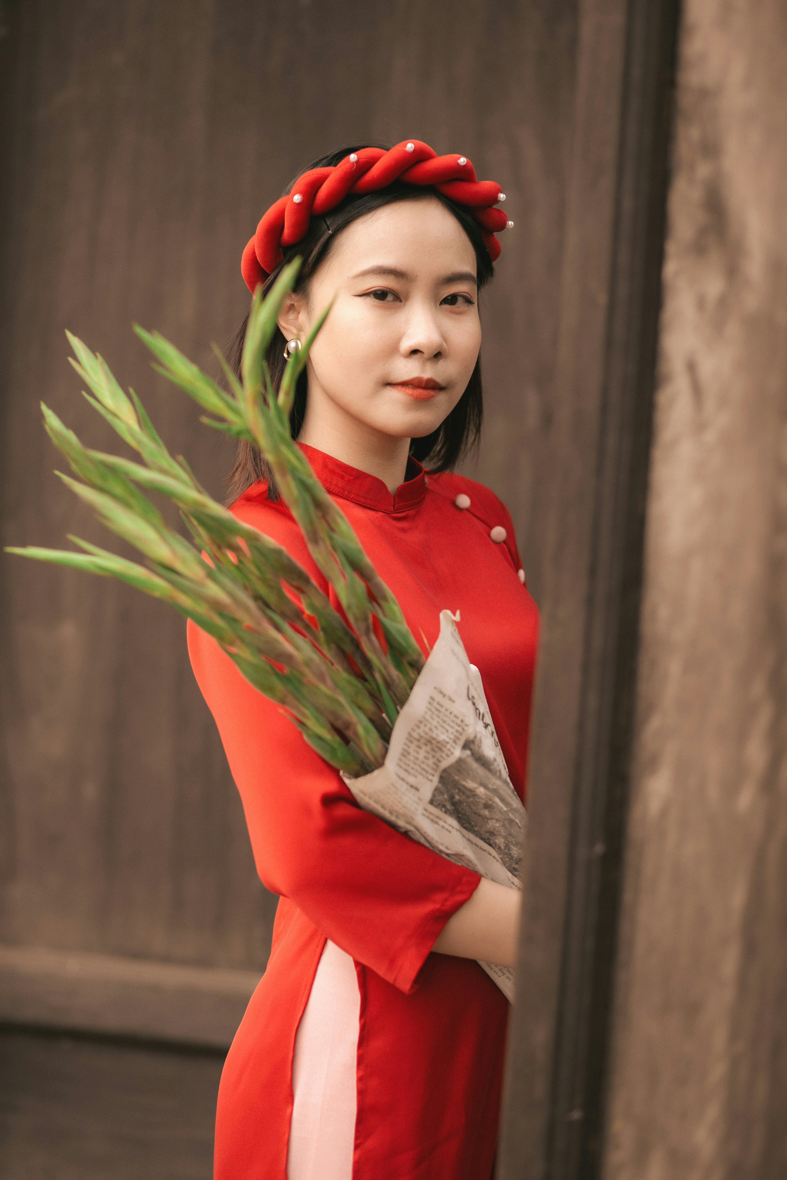 a woman in a red dress holding a bunch of green plants