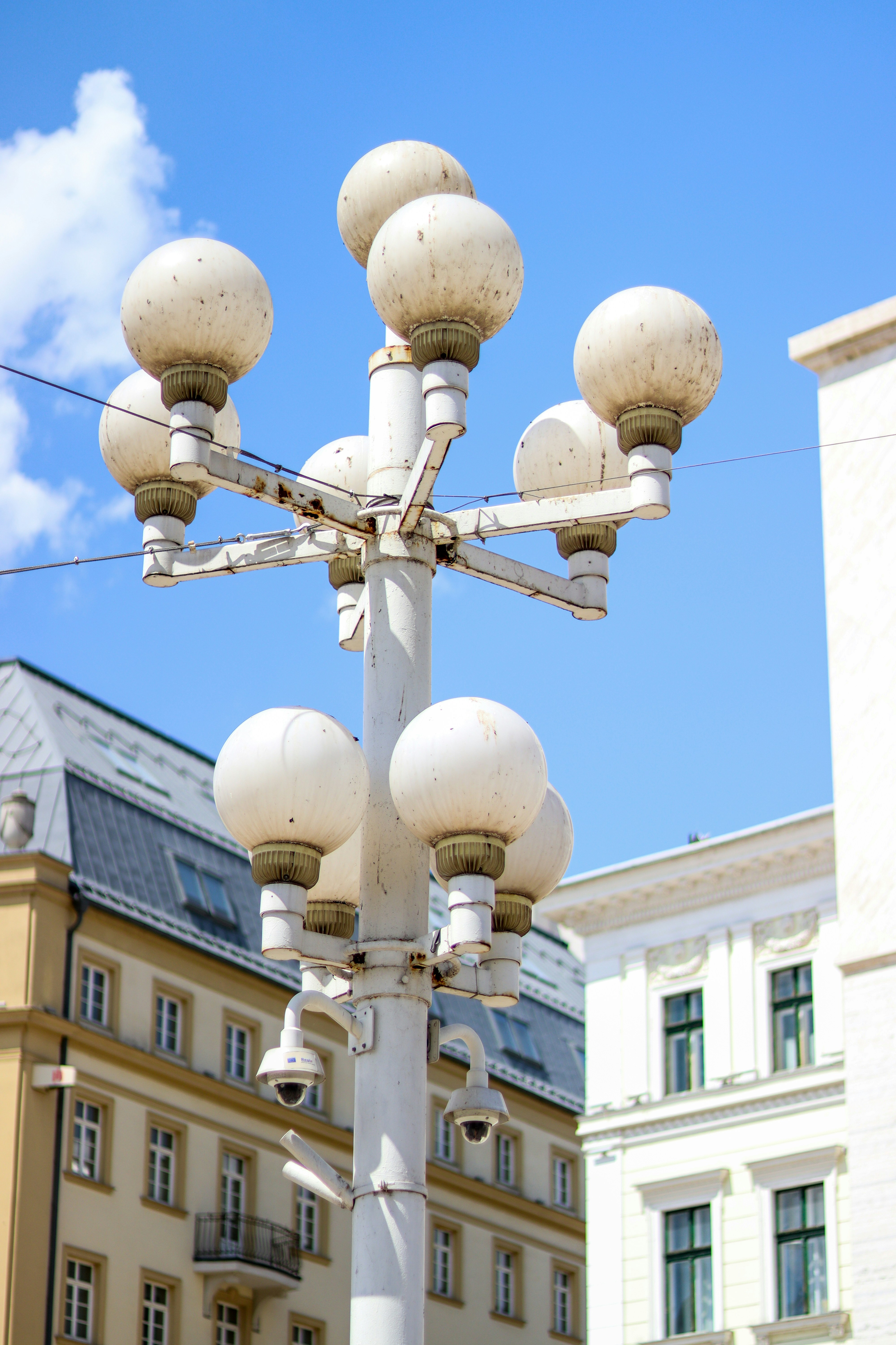 Orb-Cluster Lanterns Rising Above a Sunlit Town Facade