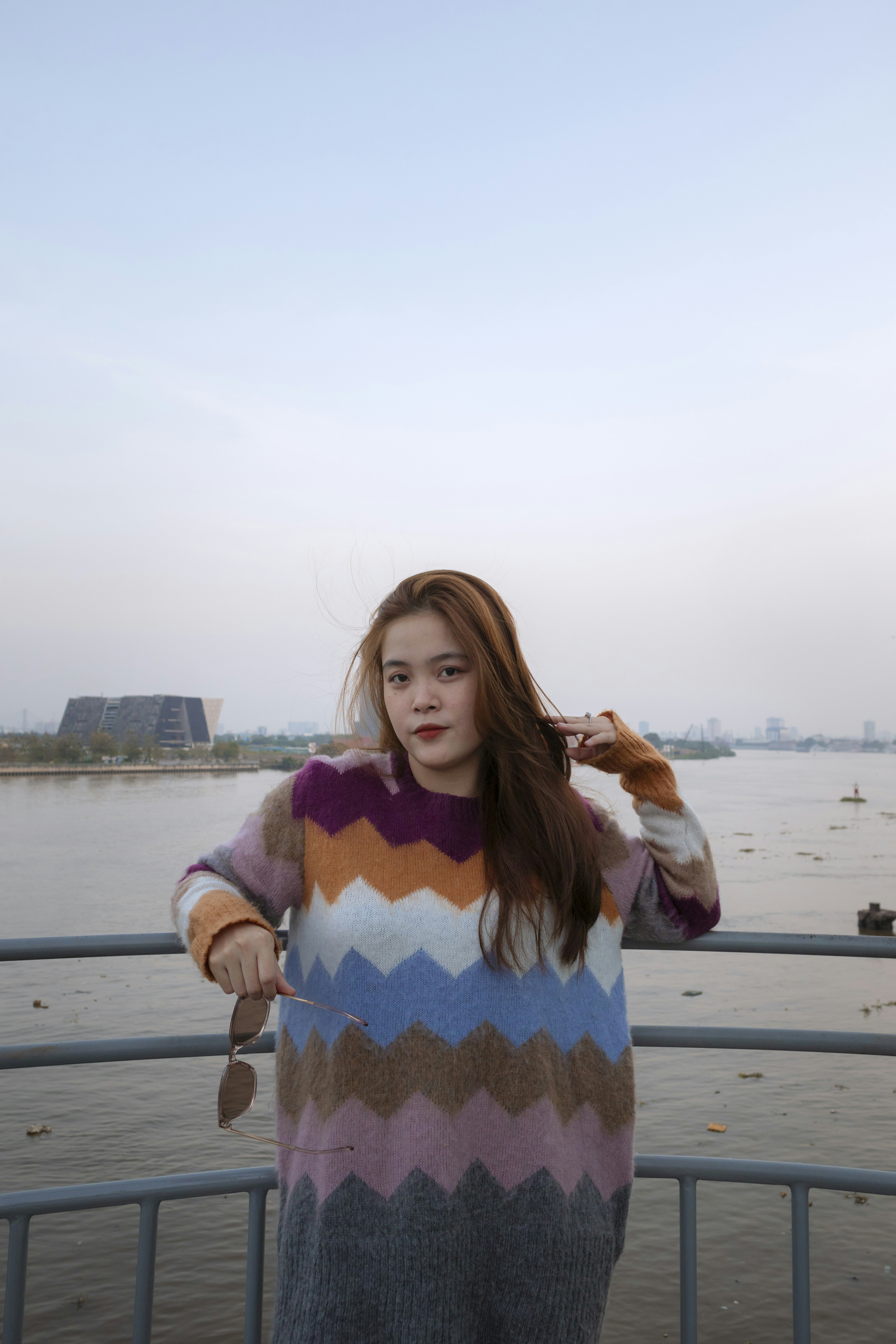 a woman standing next to a railing near a body of water