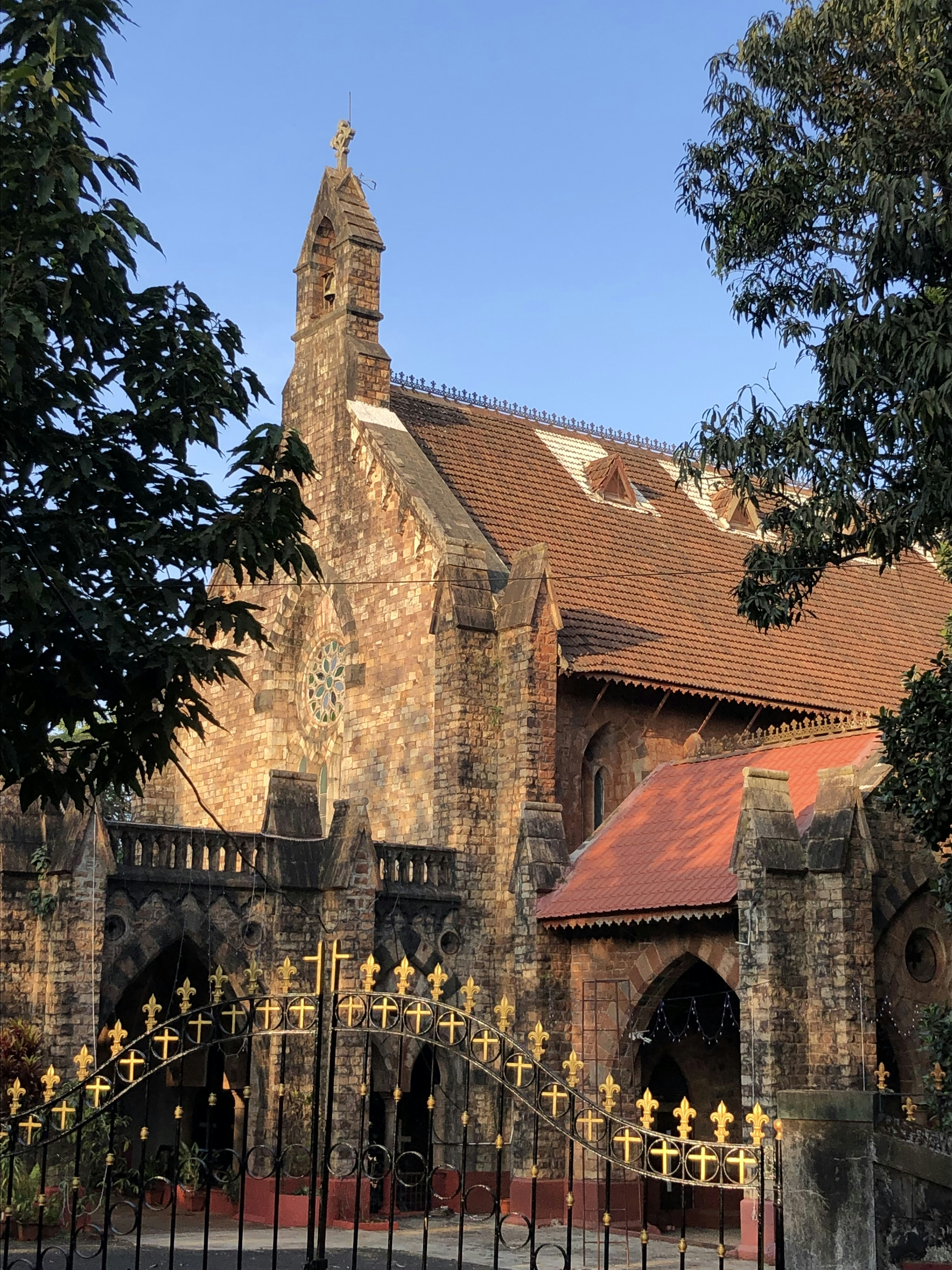 Historic church with a stone facade, ornate gate, and clock tower under a clear blue sky.