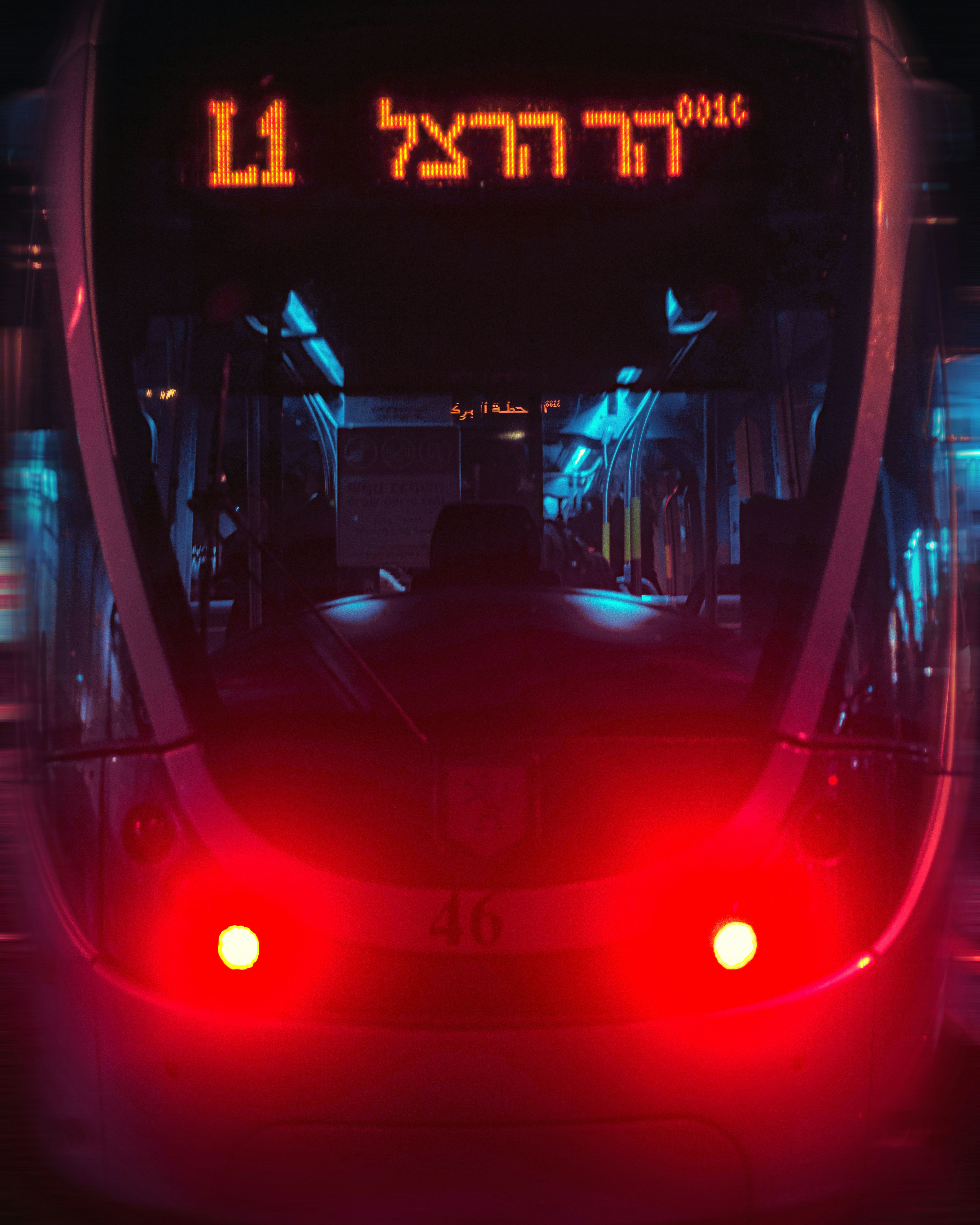 a red bus is parked at a bus stop
