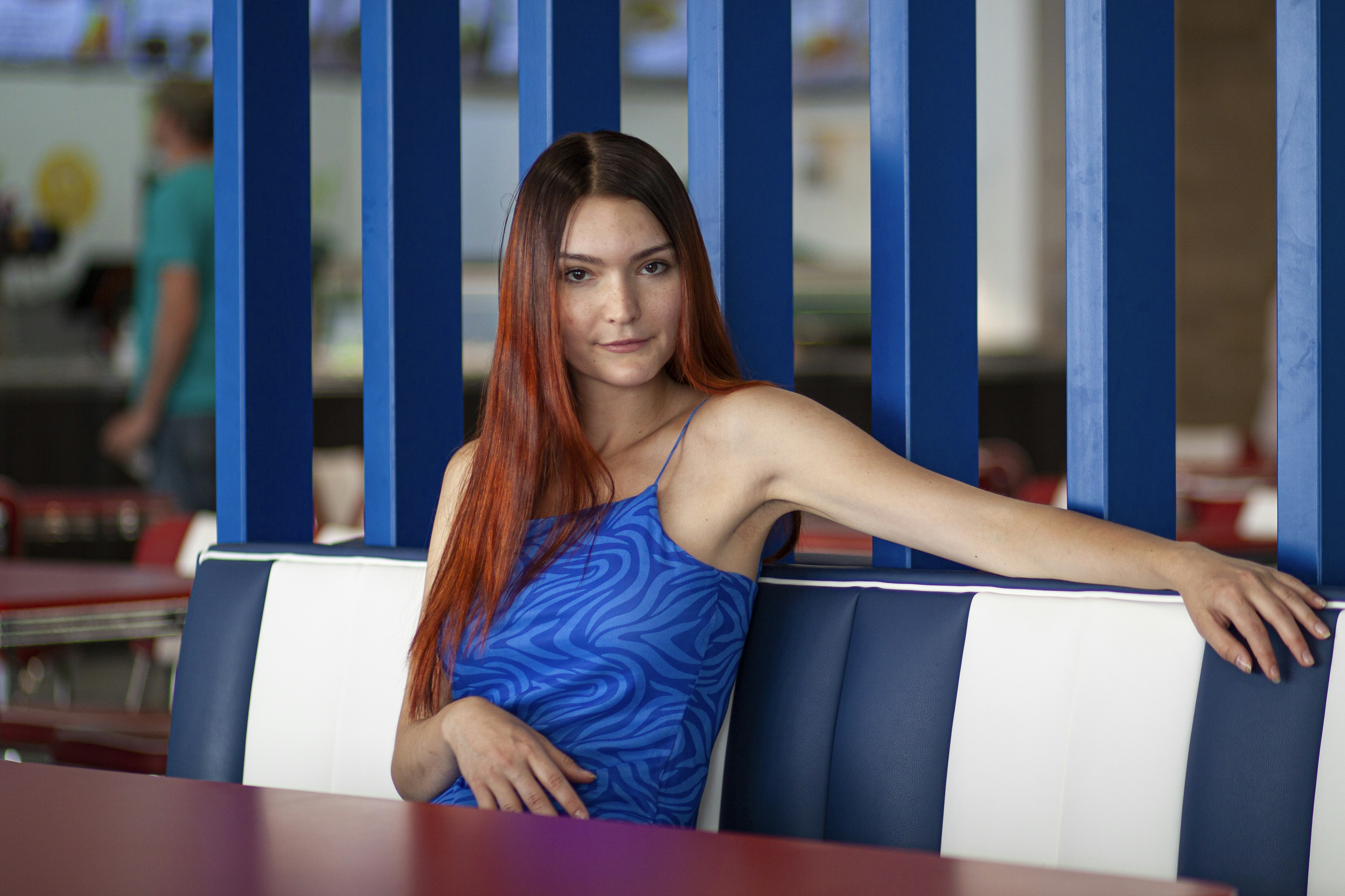 Woman in a blue dress seated at a modern table with vertical blue accents.