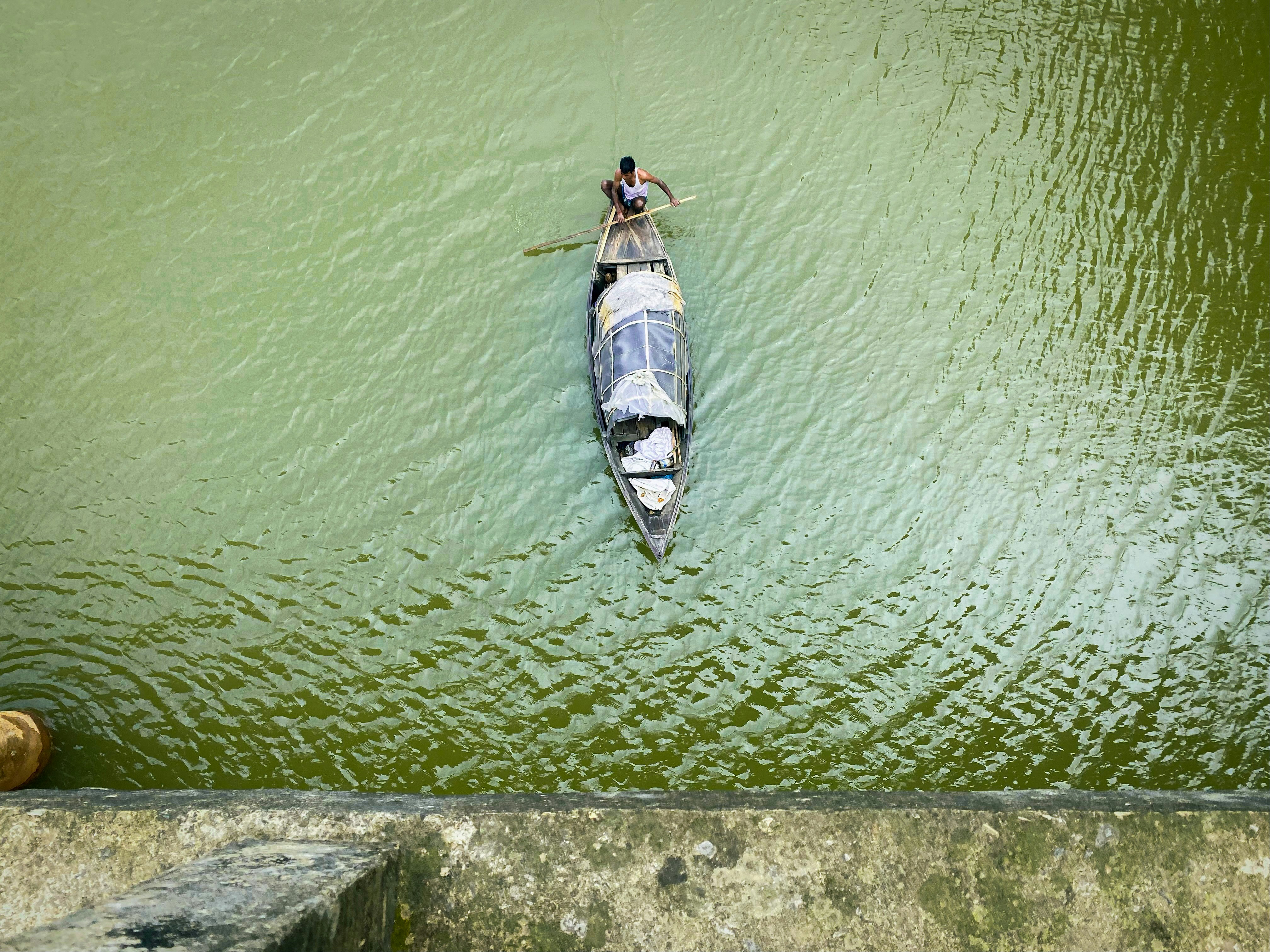 Emerald Lullaby: A lone rowboat threads through glassy green water