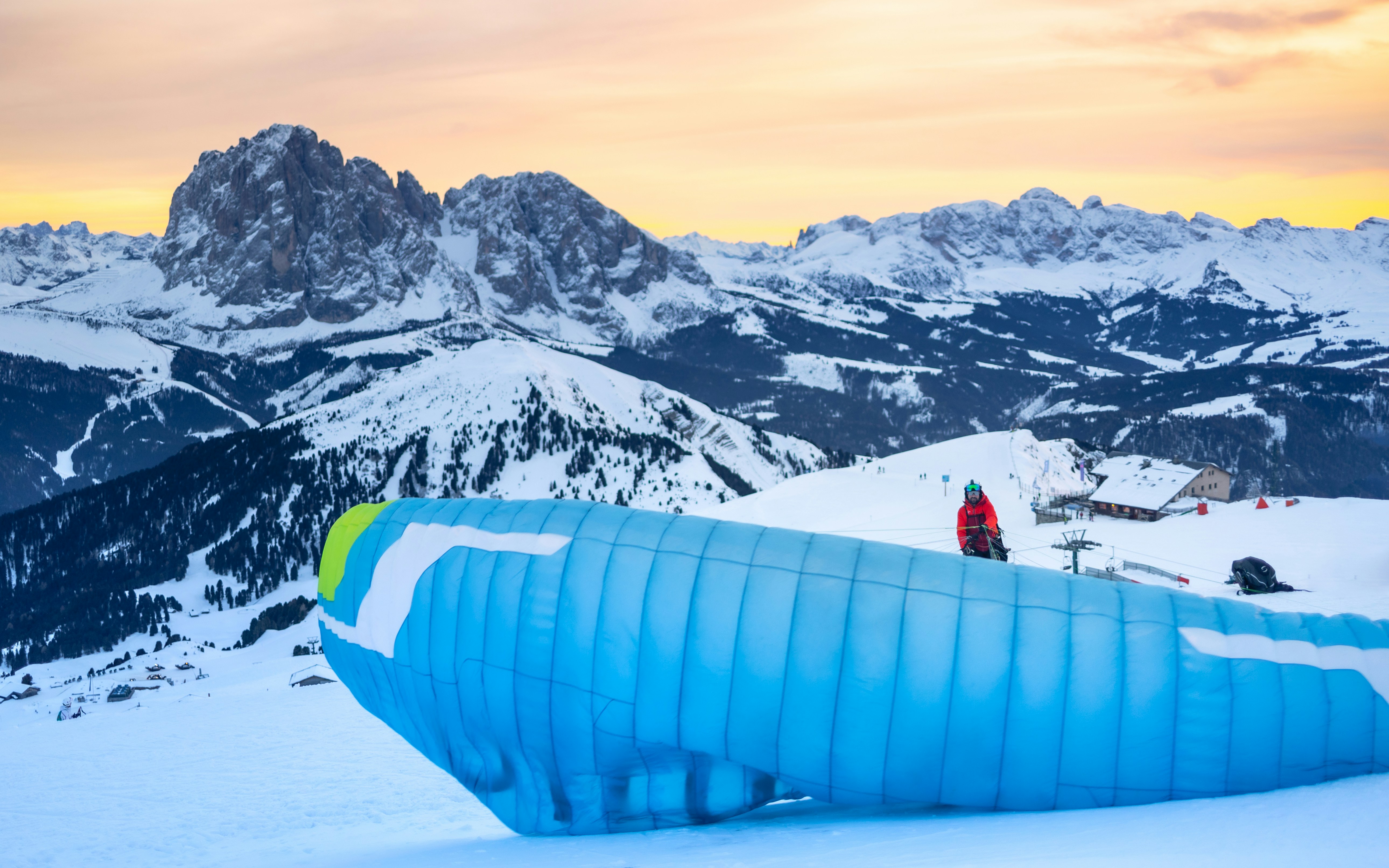 Blue Paraglider Wing on Snow as Alpine Sunset Colors the Peaks