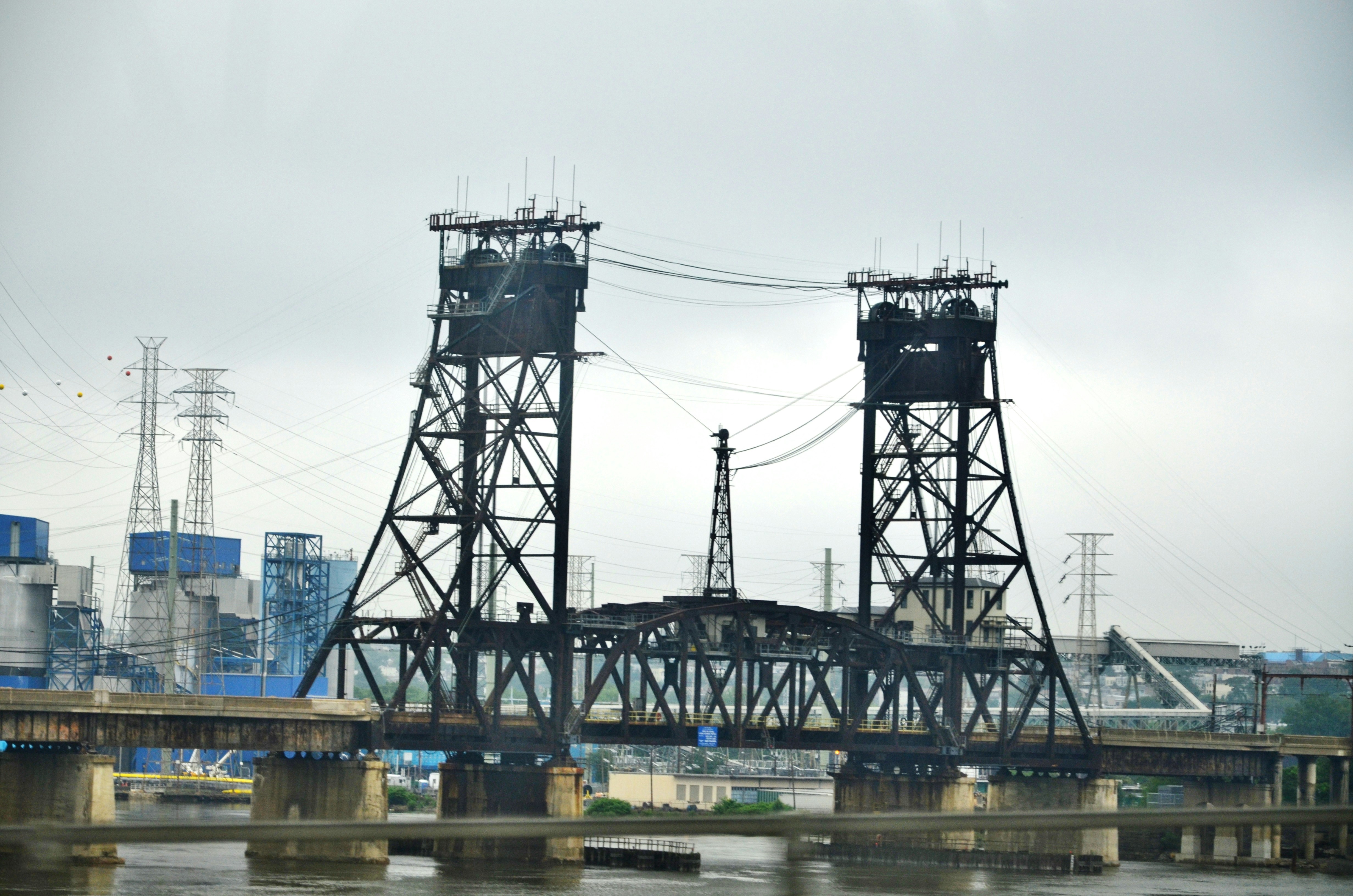 A large bridge over a river with power lines above it photo – Free ...