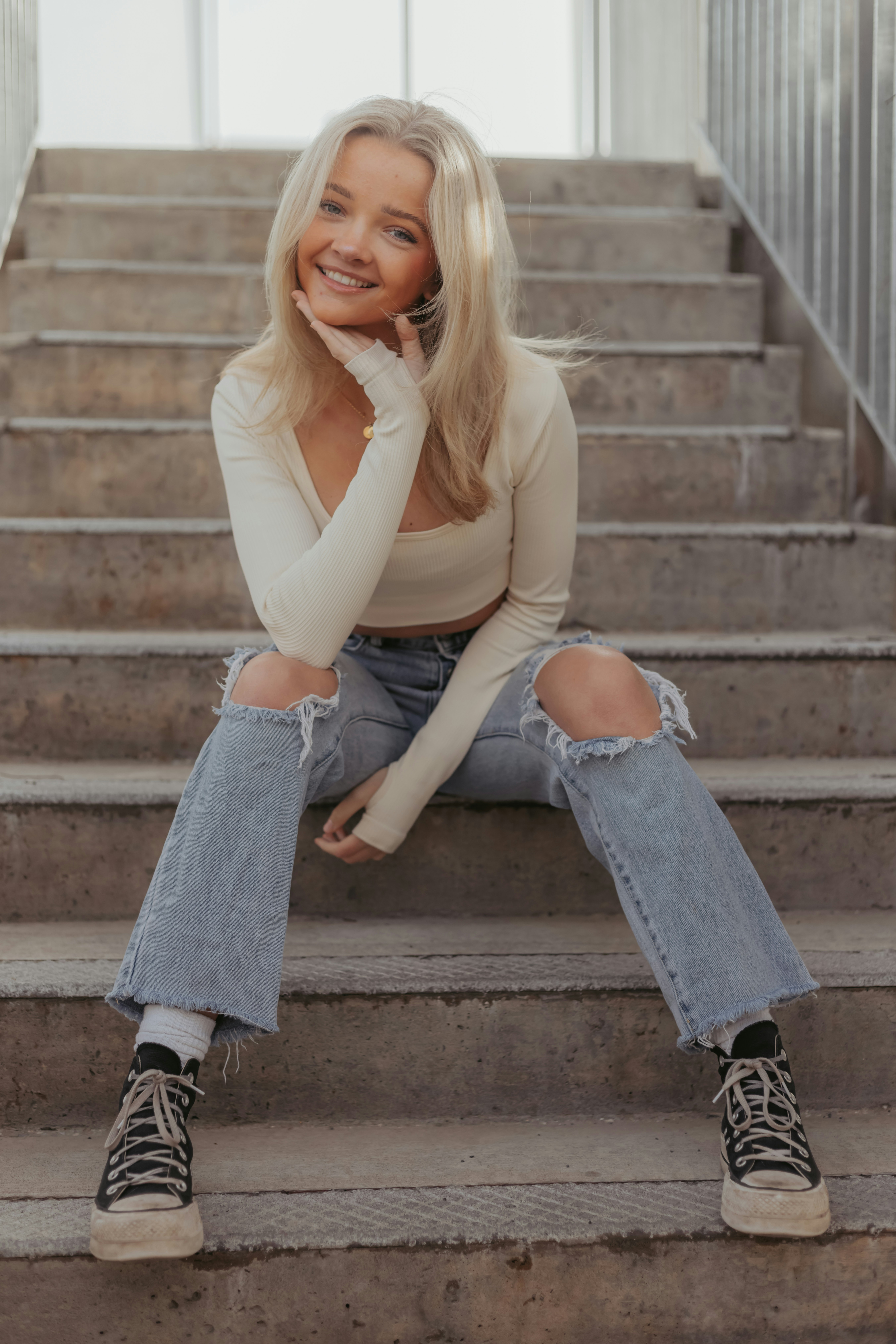 A woman sitting on the steps of a building photo – Free Jeans Image on ...