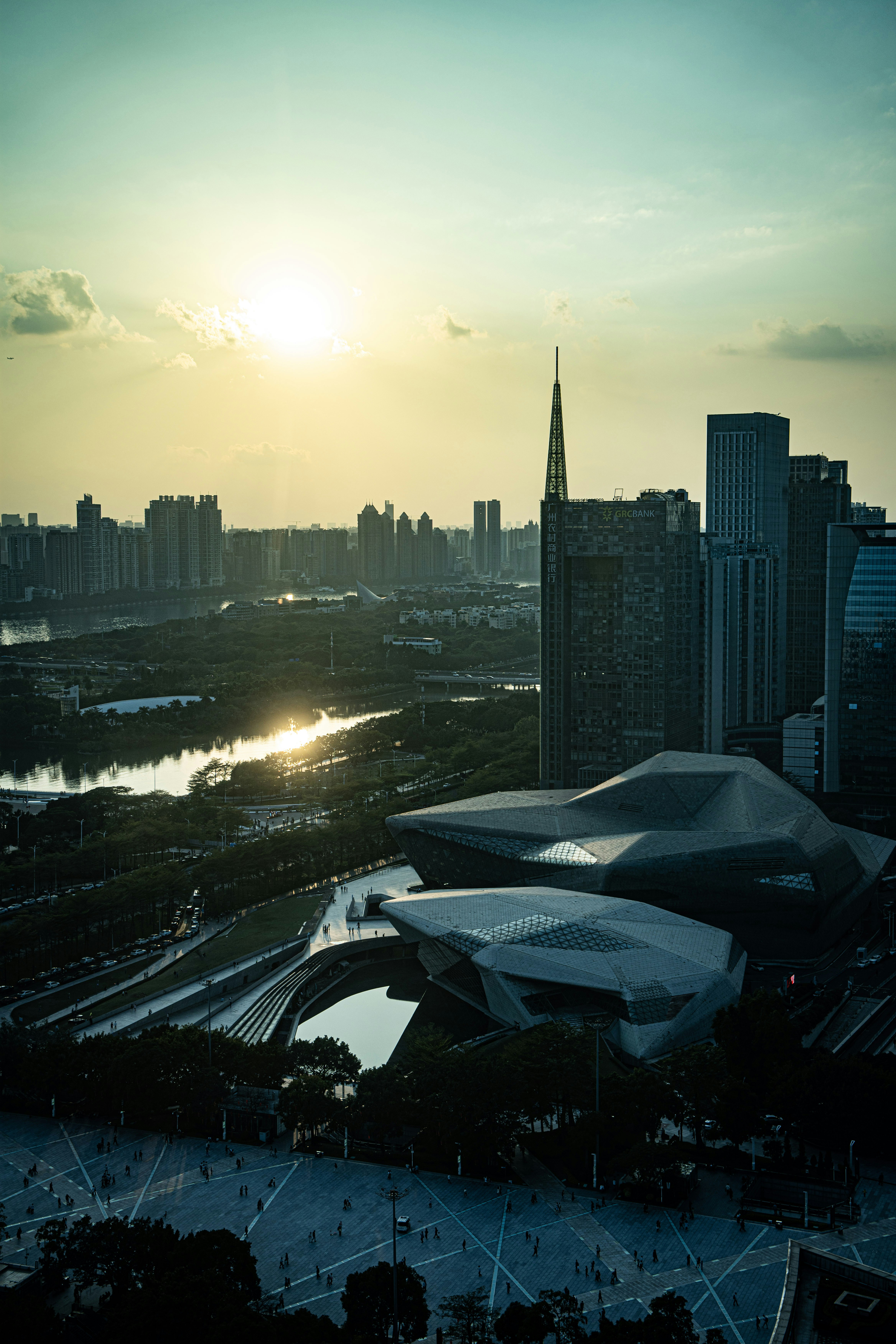 Sunrise Over a Crystalline Cityscape: River, Skyscrapers, and Angular Pavilions