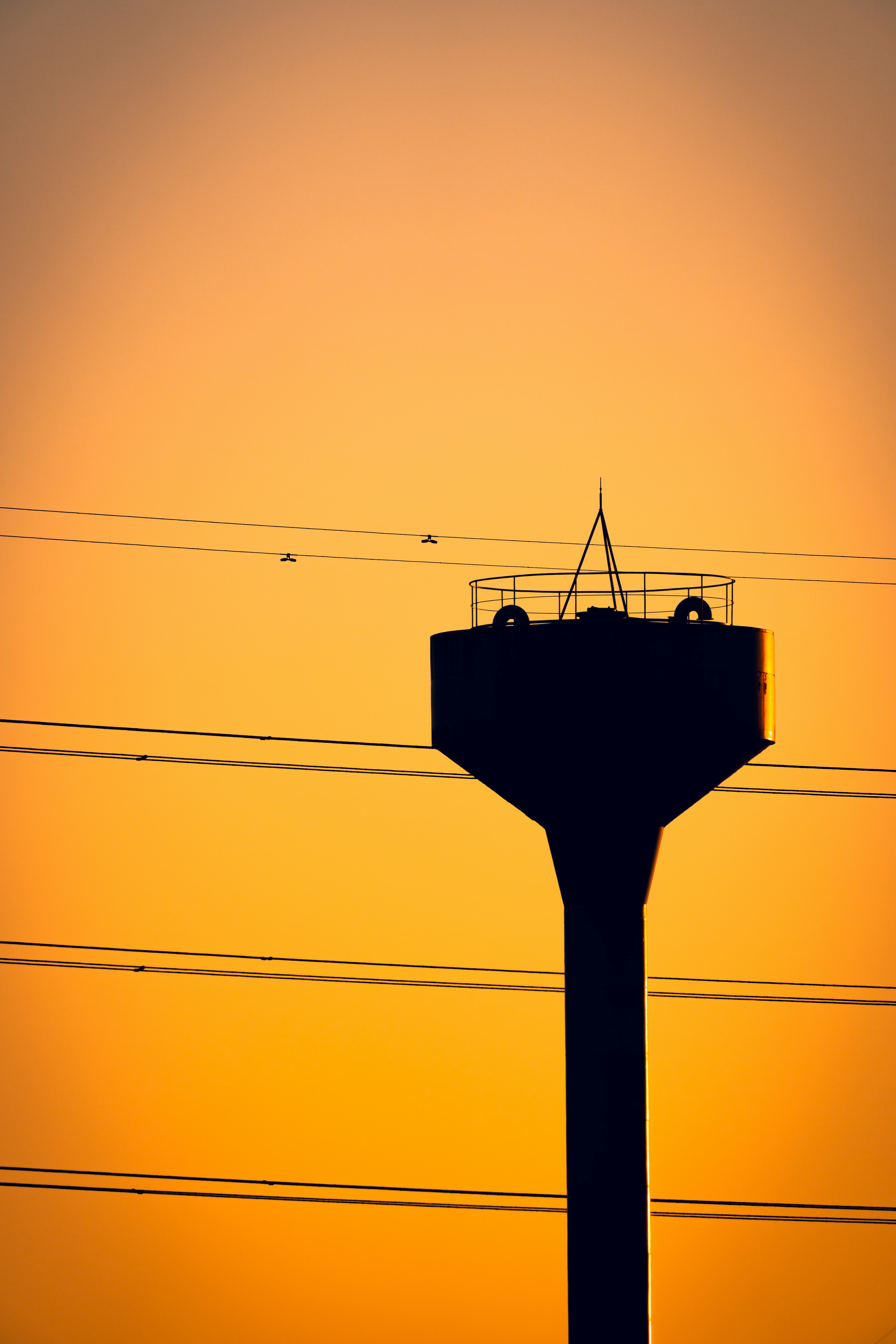 Molten Orange Silhouette: Water Tower Framed by Wirelines