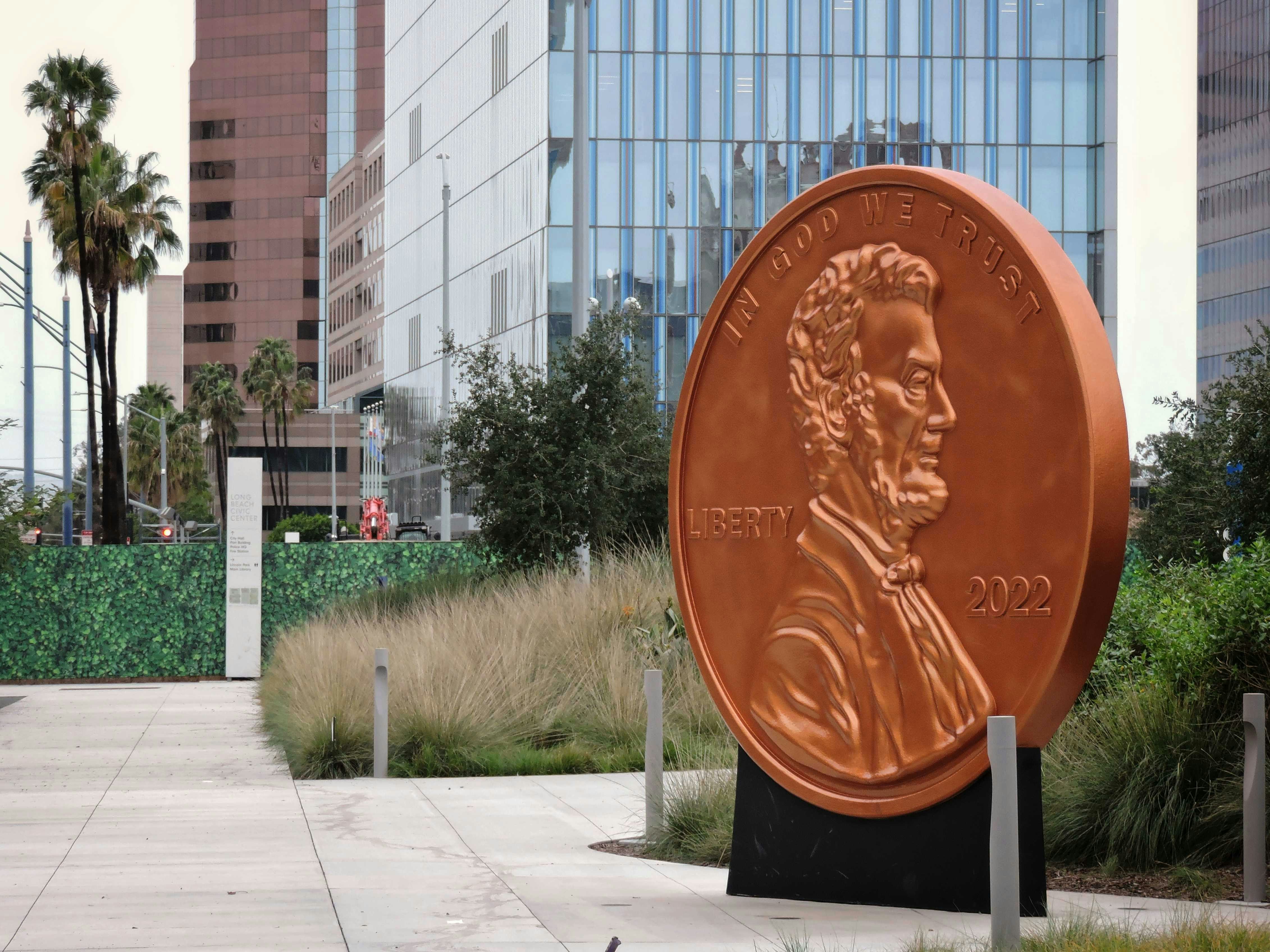 A bronze coin sitting on top of a sidewalk next to tall buildings photo ...