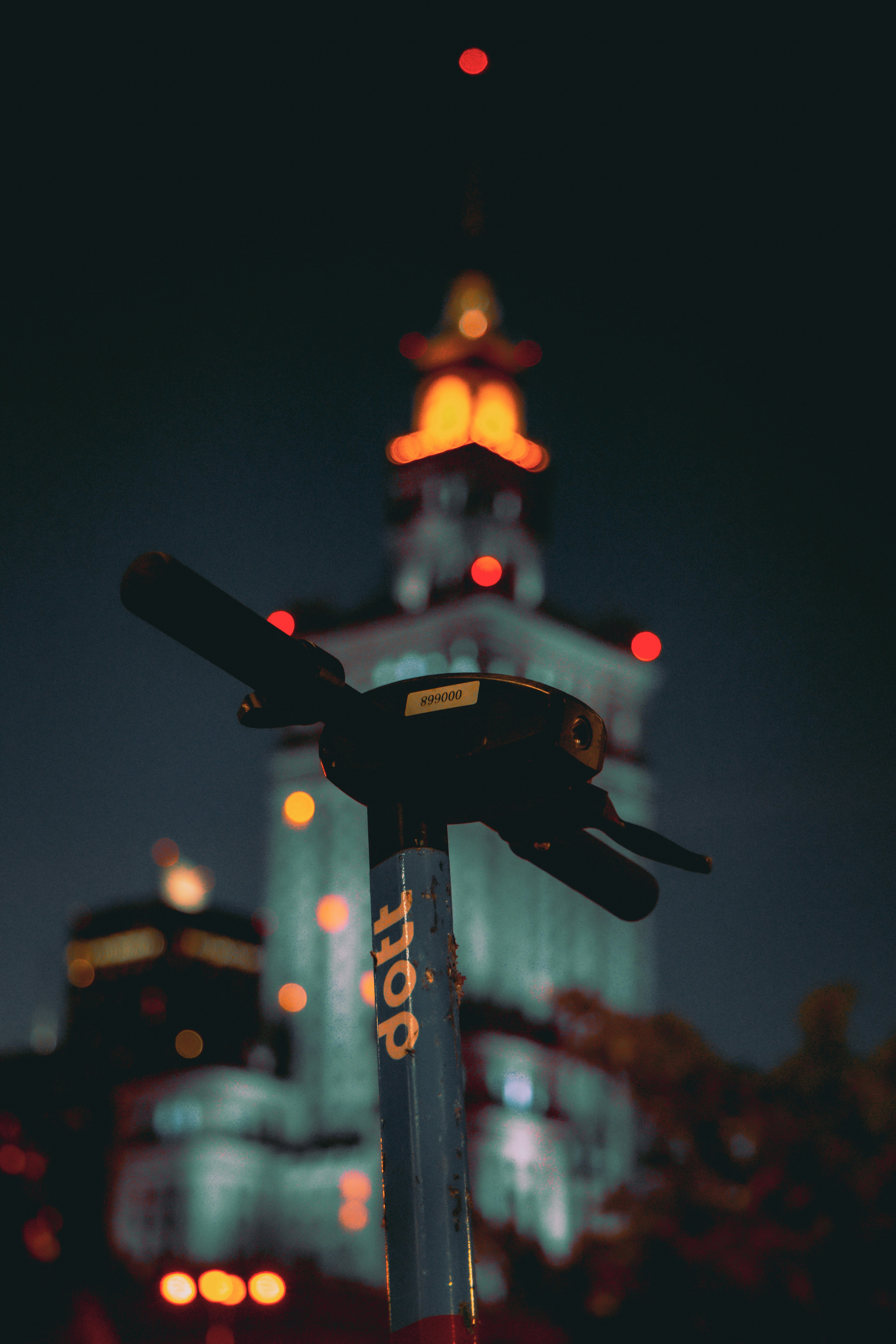 Midnight Stand Under Neon: A Scooter Foreground with a Glowing Tower