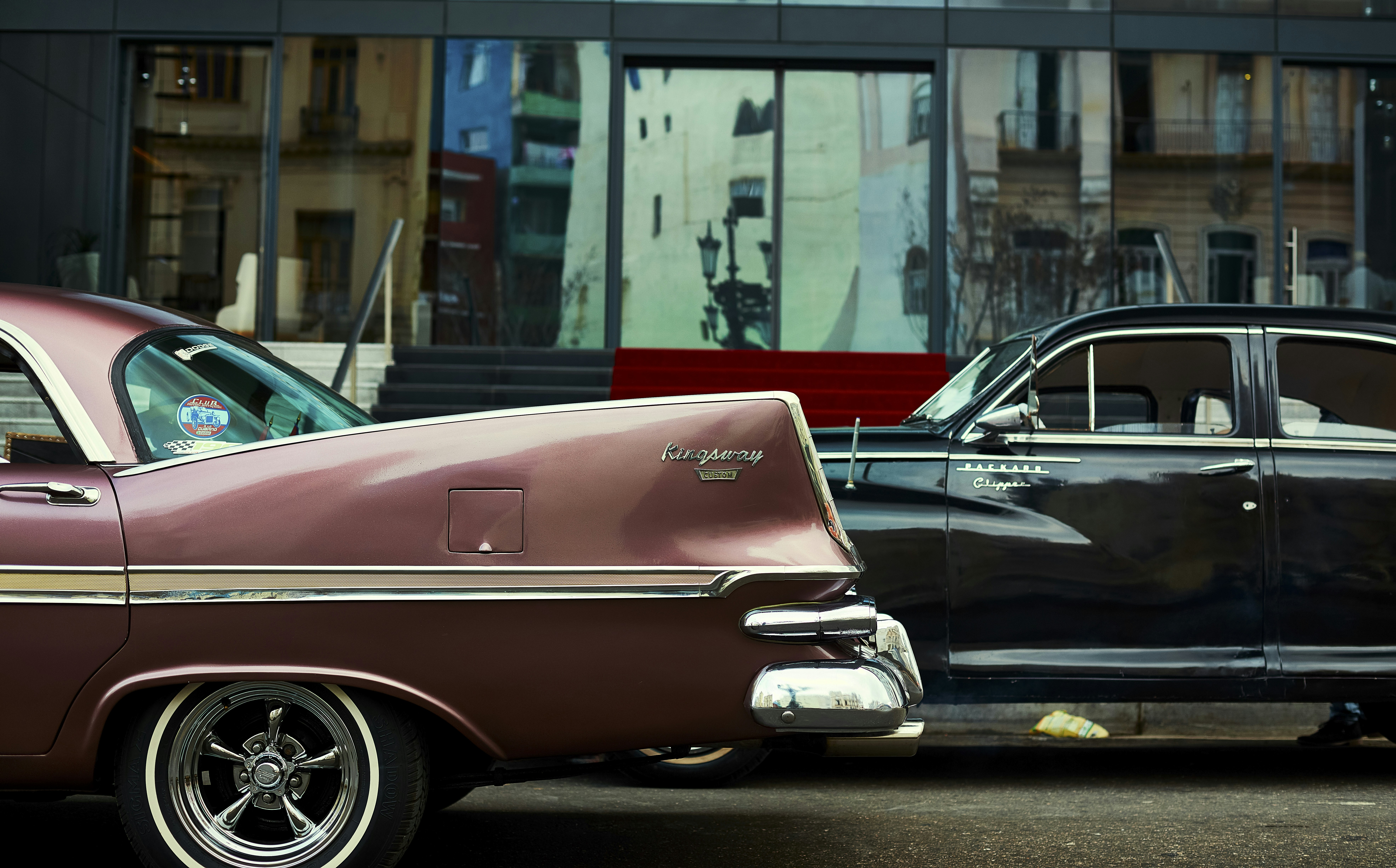 Two old cars parked next to each other in front of a building photo ...