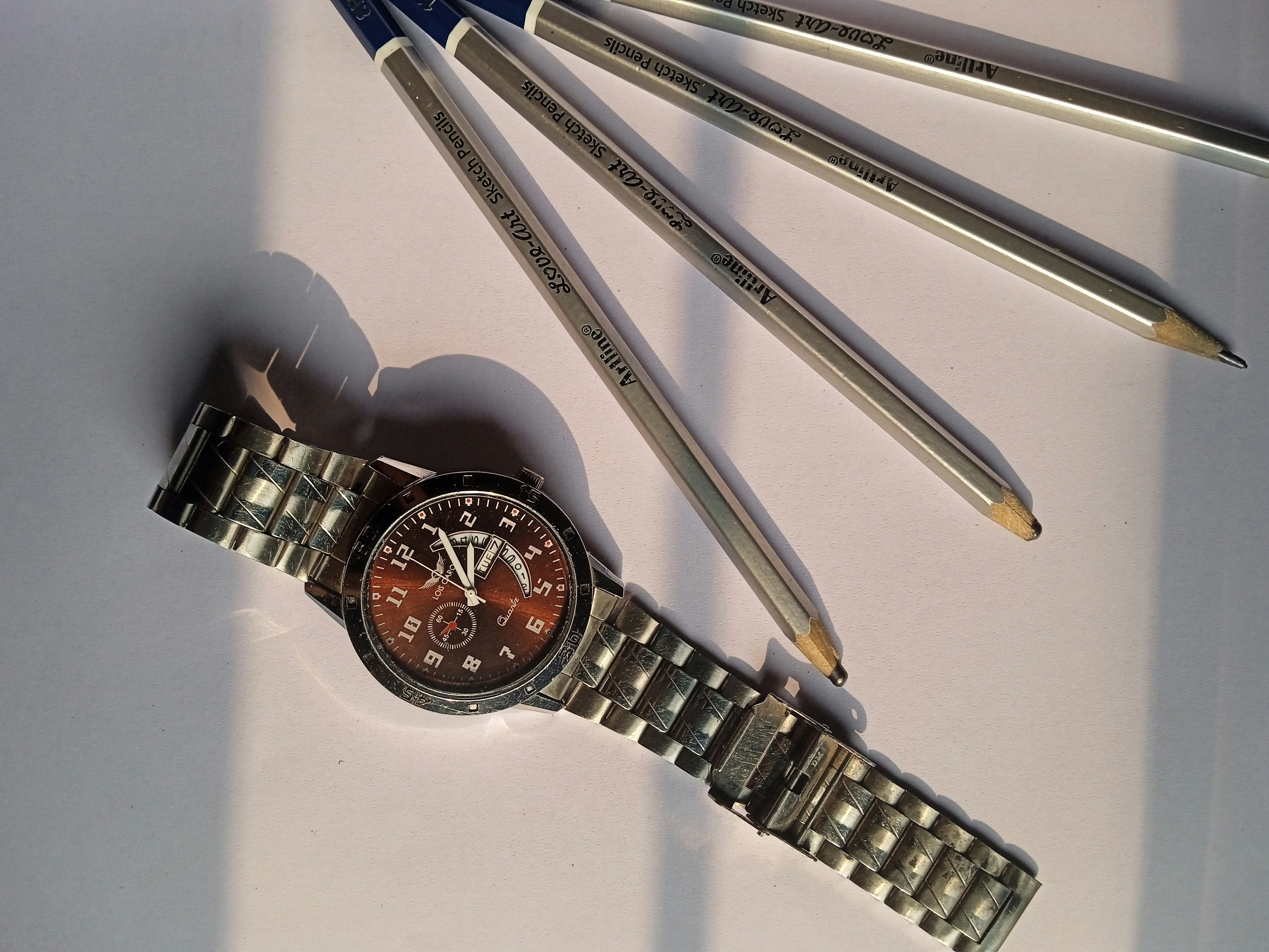 A watch and some pencils on a table photo – Free White background Image ...