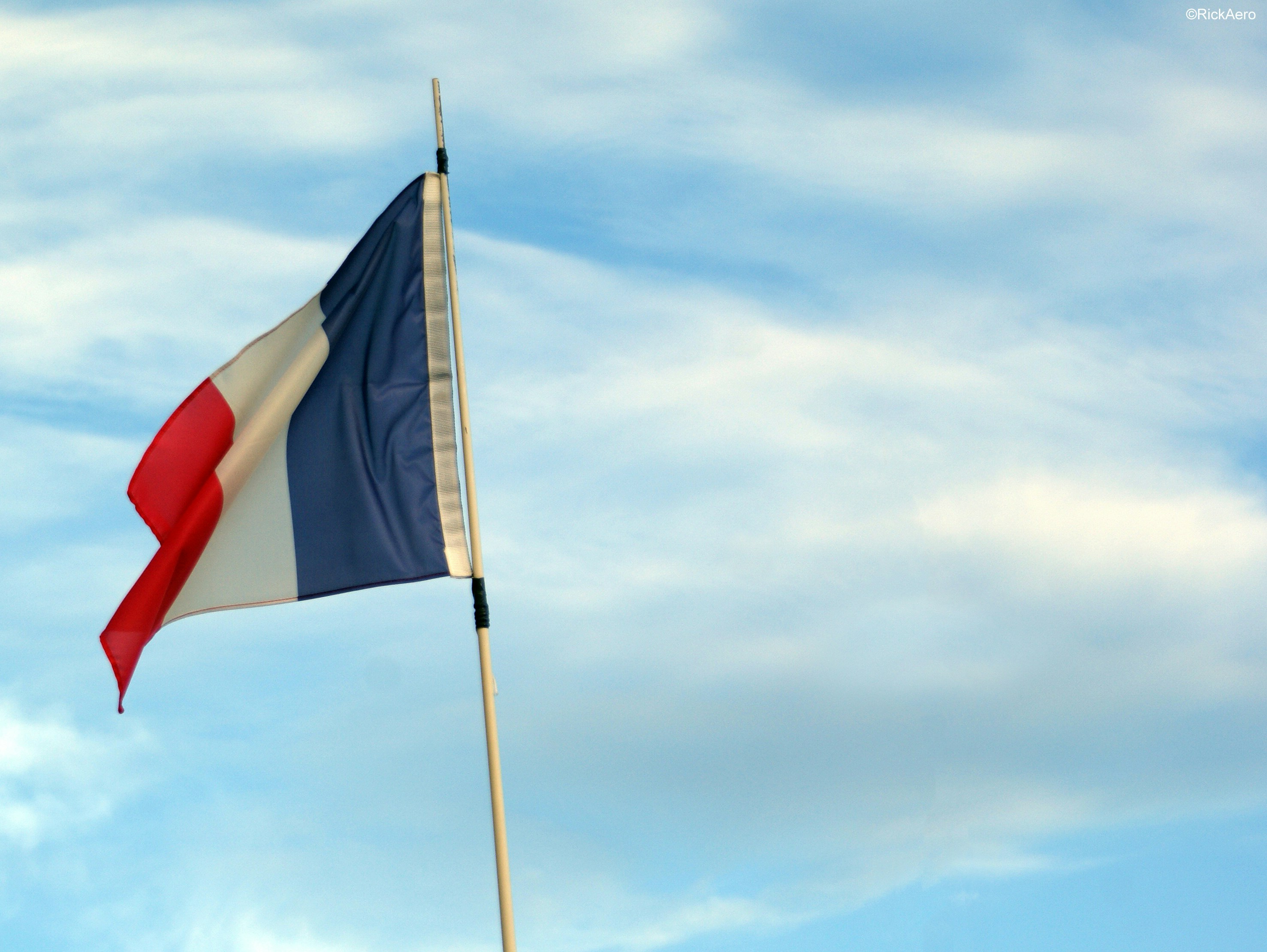 French flag fluttering against a backdrop of soft blue skies, symbolizing national pride and identity.