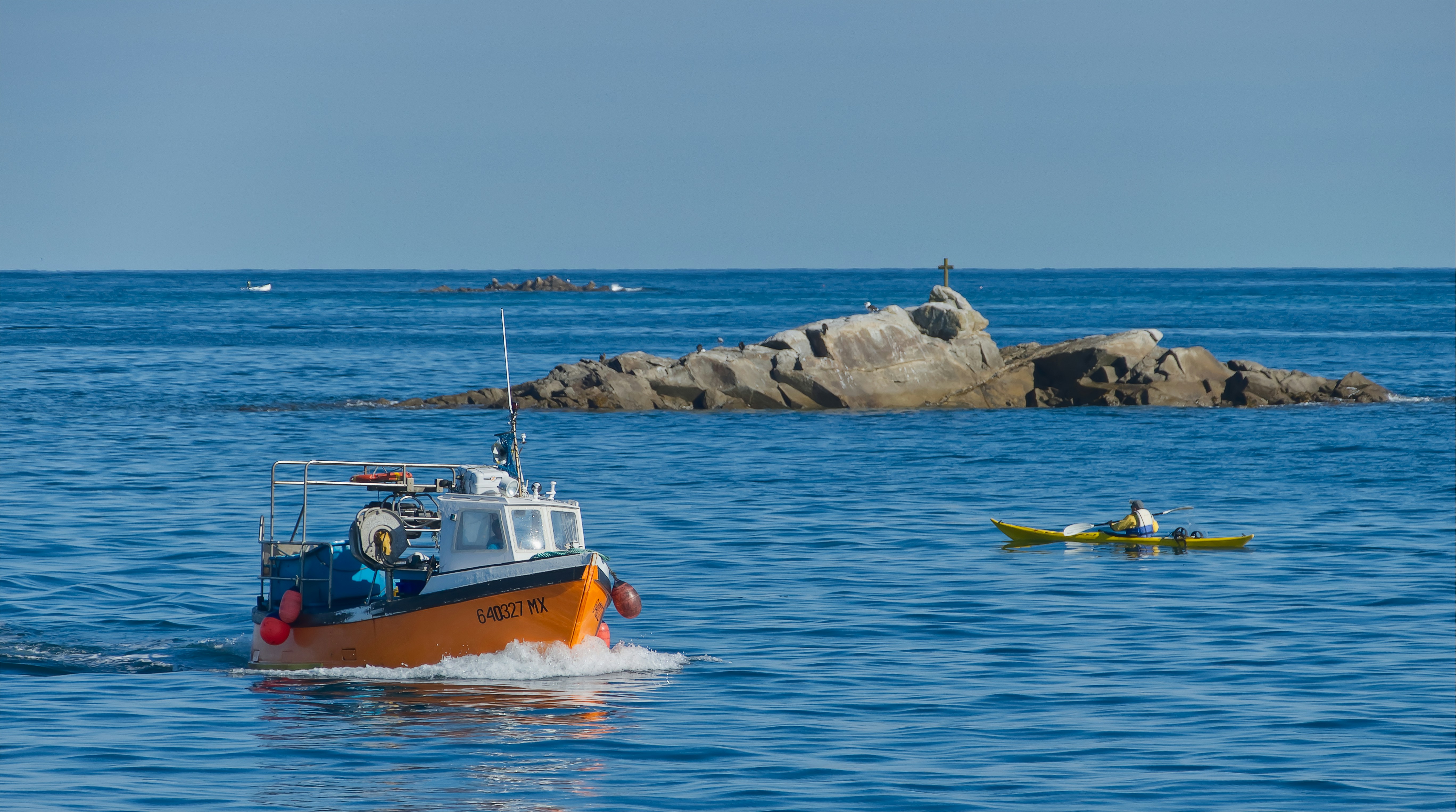 Un bateau de pêche croisant un kayak de mer dans le chenal de Roscoff passent devant la croix sur un rocher. Cette croix que l'on peut apercevoir de l'estacade de Roscoff a été érigée pour les besoins du film muet tourné en 1927 « La croix sur le rocher » par Jean Rosné et Edmond Levenq. Le film raconte l’histoire du père Le Goff, propriétaire d'un vivier de Roscoff, qui s'apprête à marier sa fille avant de découvrir les manoeuvres malhonnêtes de son futur gendre!