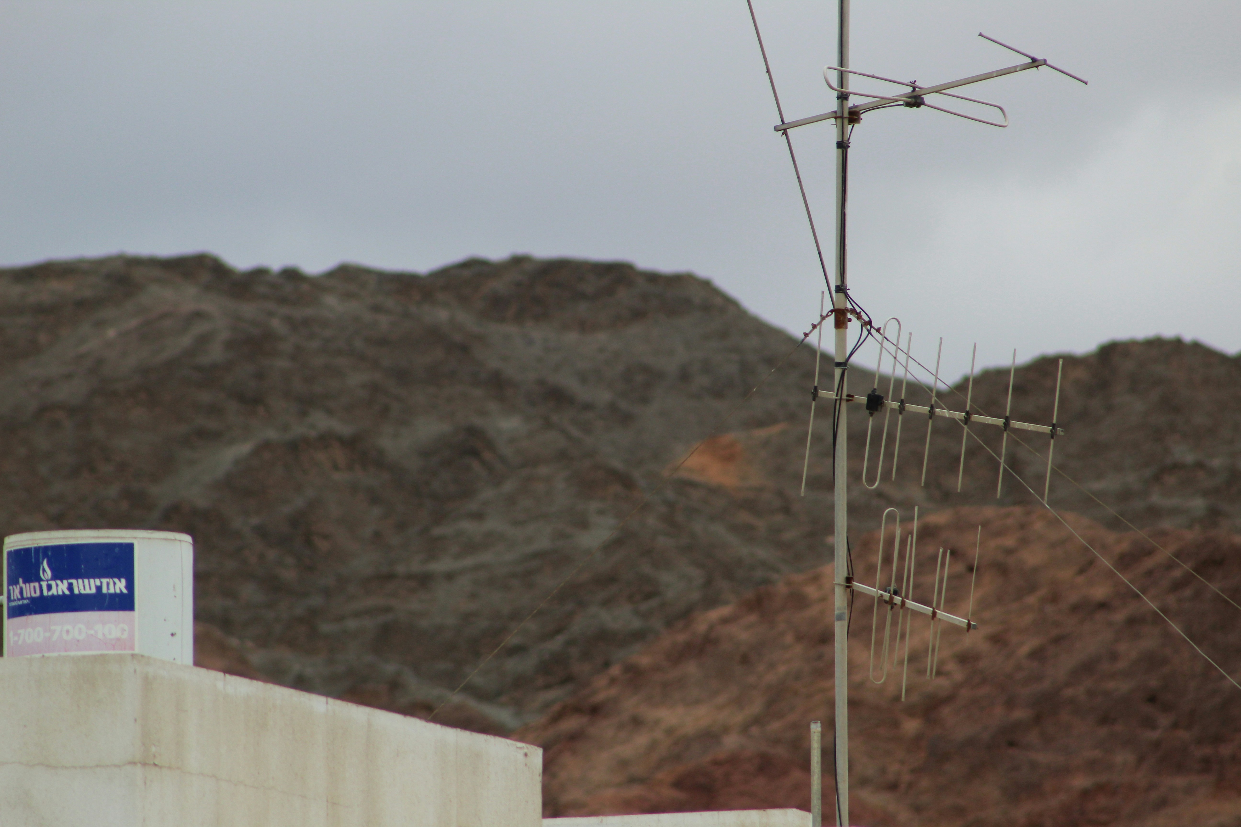 Rooftop Signals: Antenna Lines Against Eroded Hills
