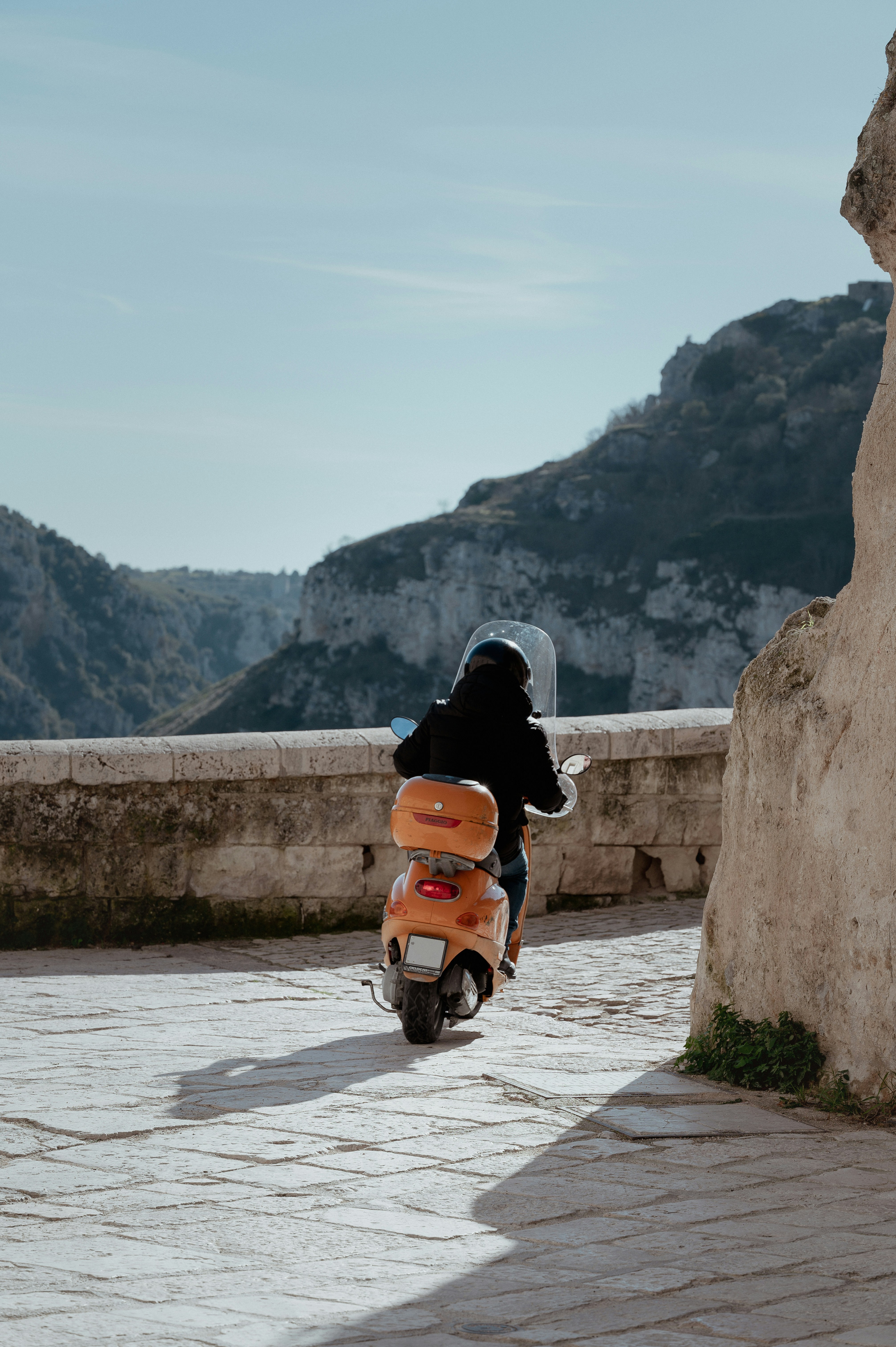 a person riding a scooter on a cobblestone road
