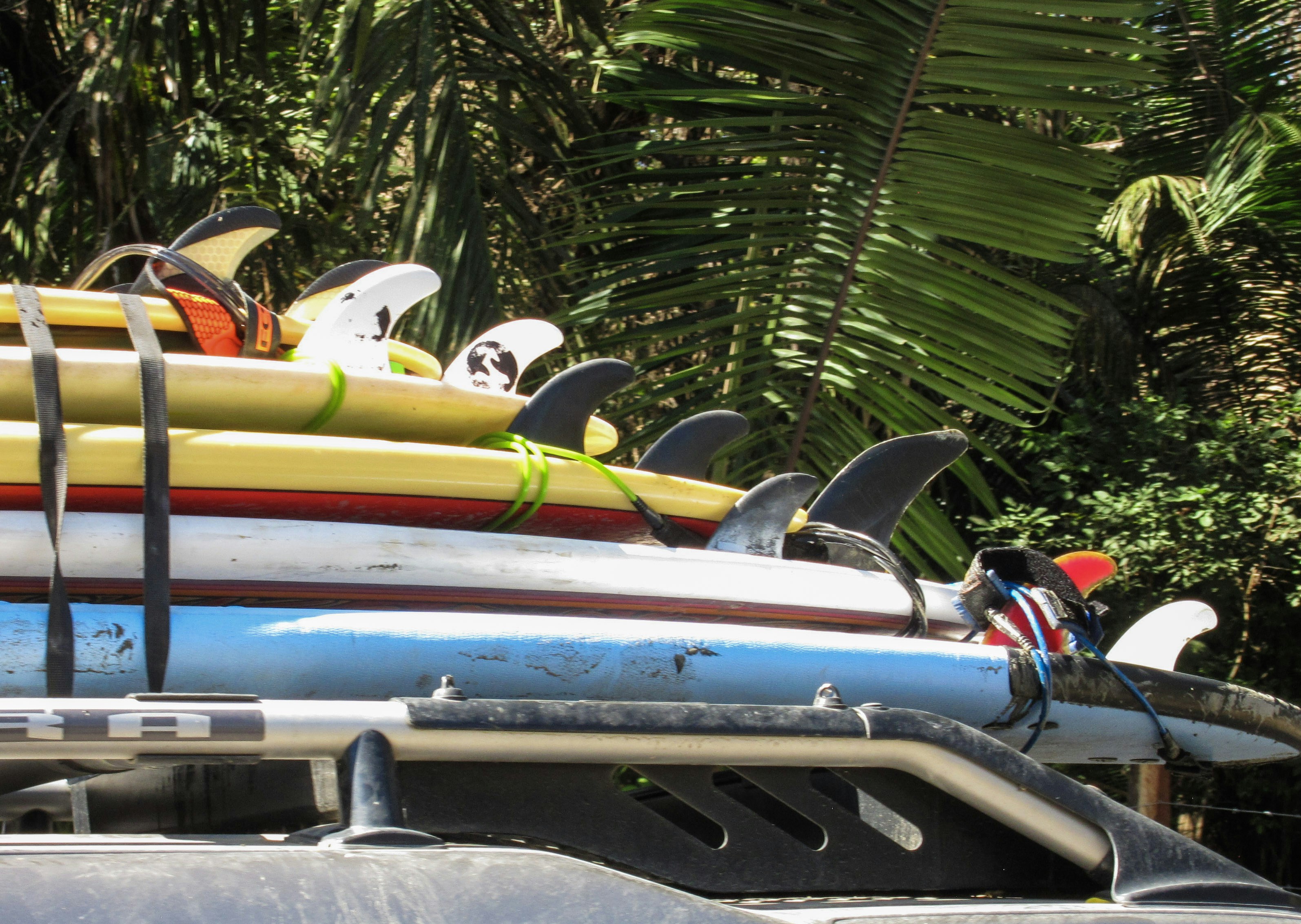 Surfboards strapped to the top of a car | a bunch of surfboards stacked on top of each other