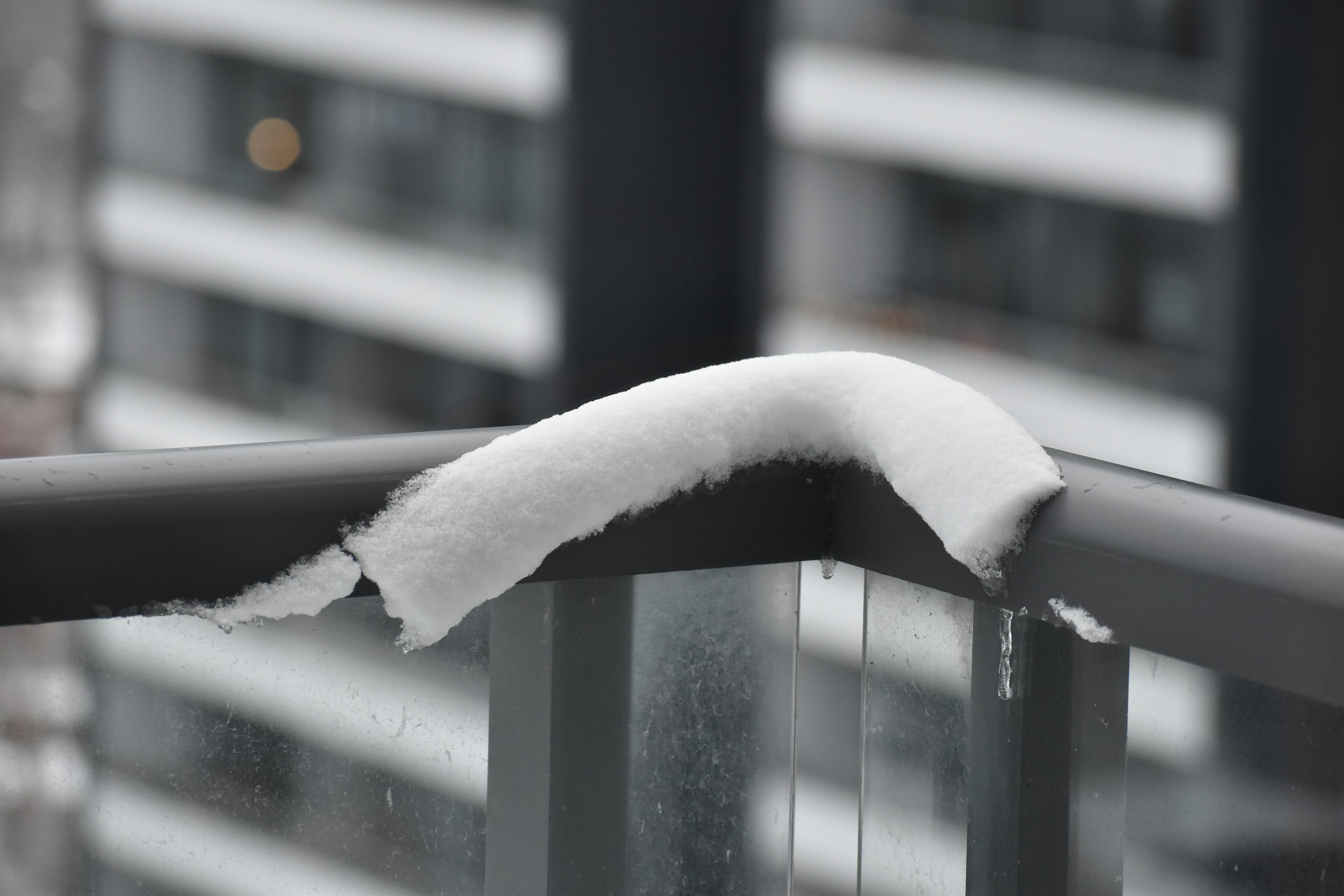 A snow covered balcony railing with a building in the background photo ...
