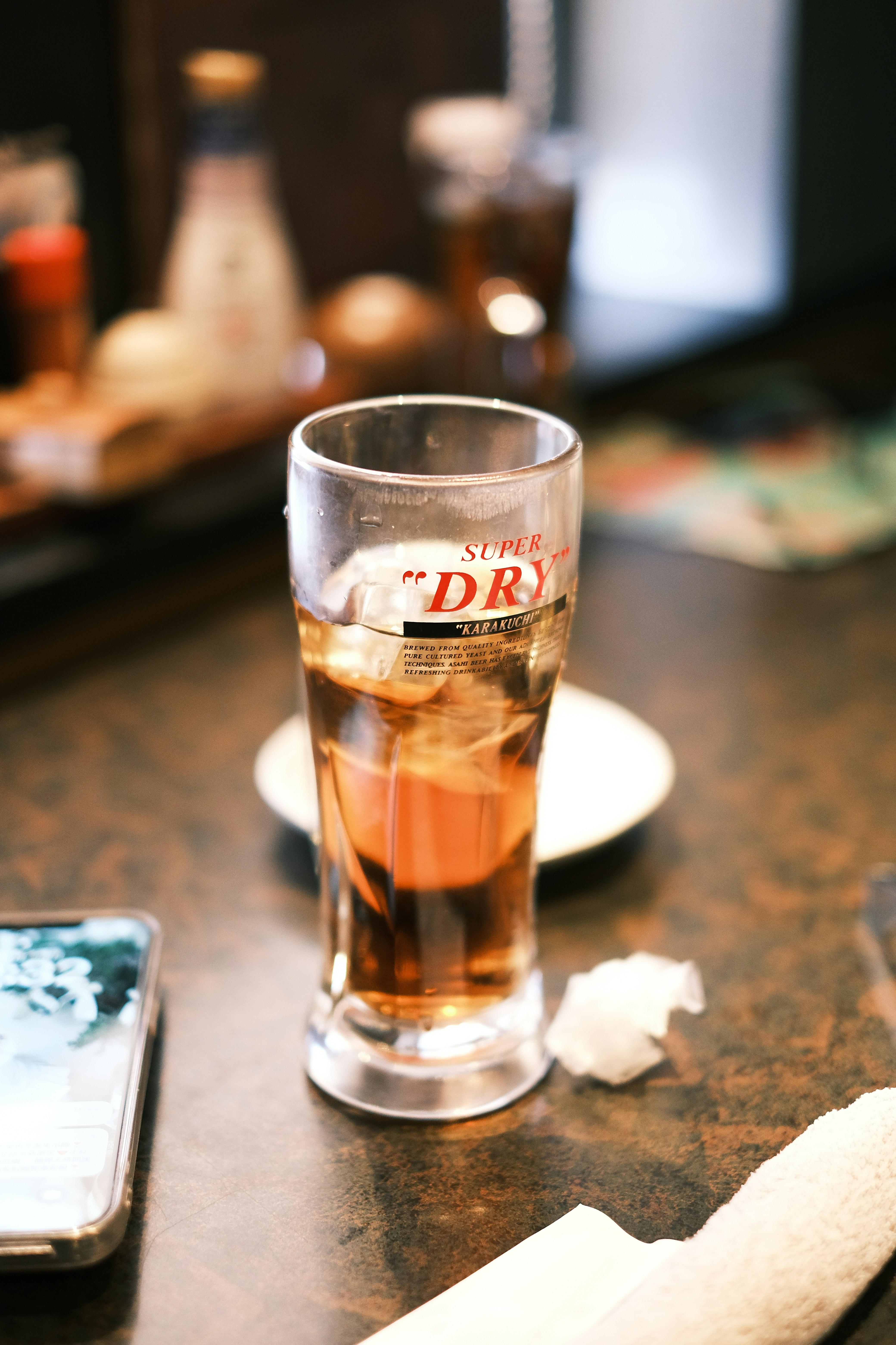 Amber Draft Under Bar Lights: Focus on a Tall Glass Amid Gentle Backdrop Blur