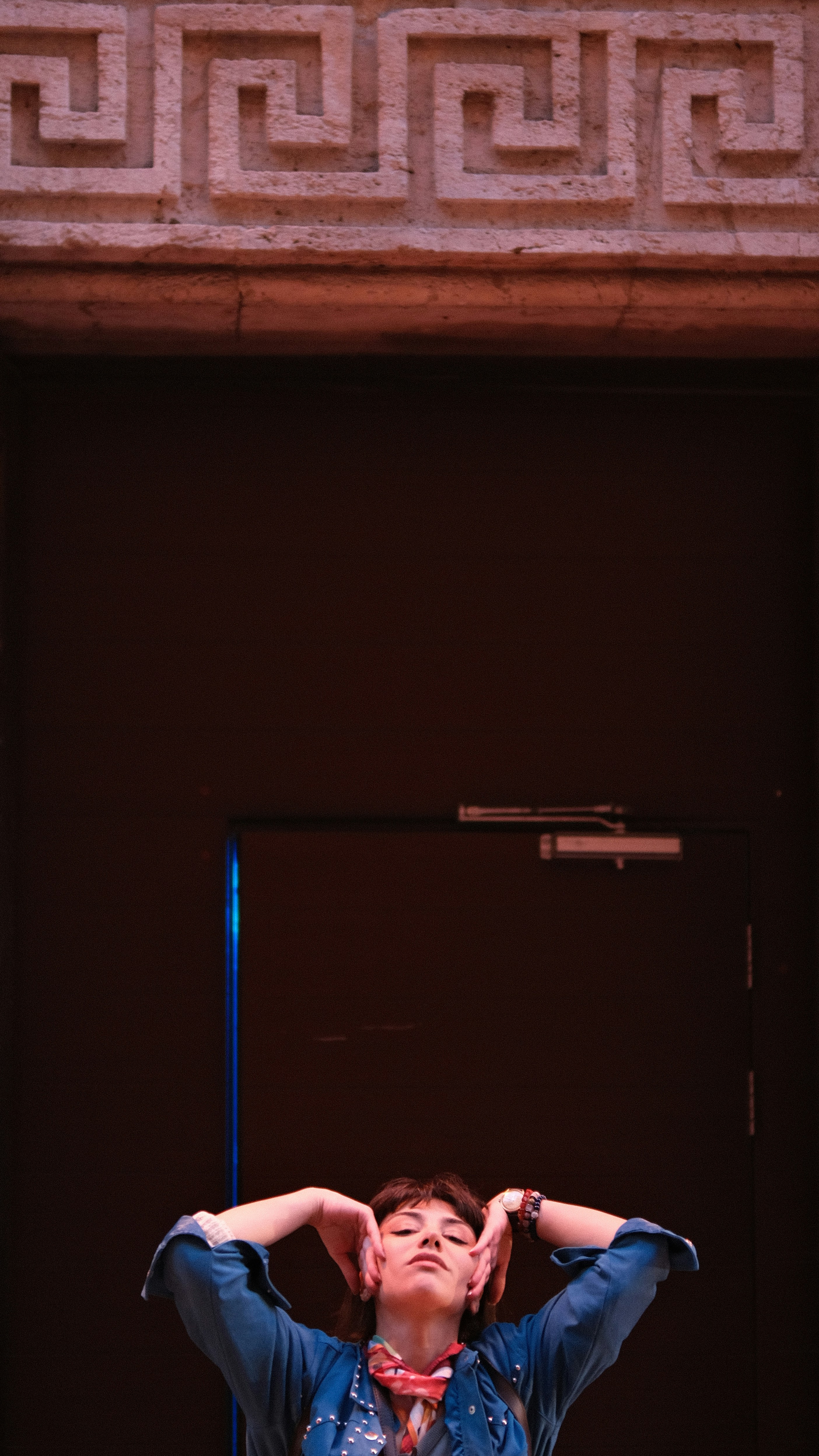a woman standing in front of a doorway with her hands on her head