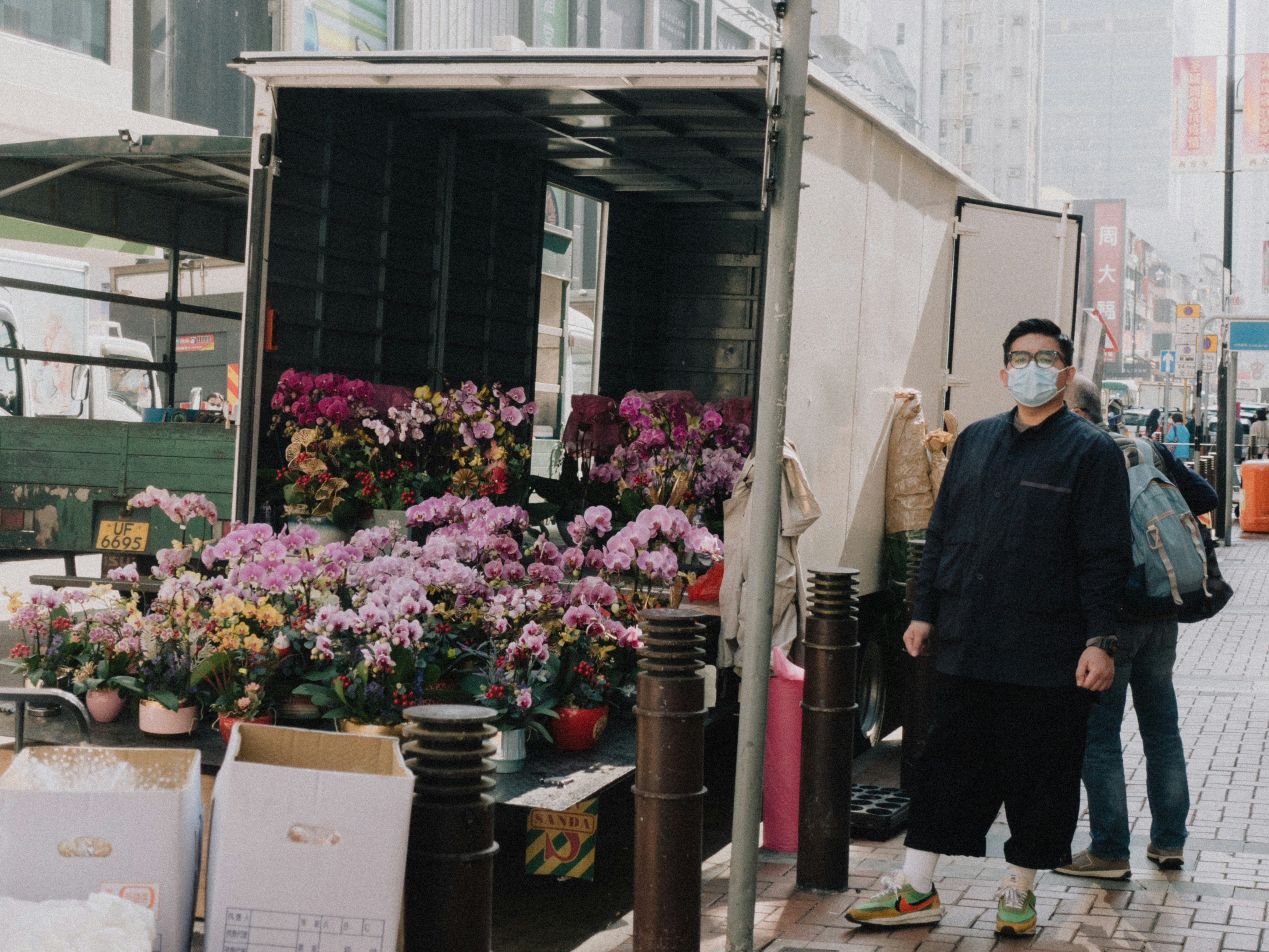 Bloom Cart on a City Sidewalk: A Quiet Moment with a Masked Observer