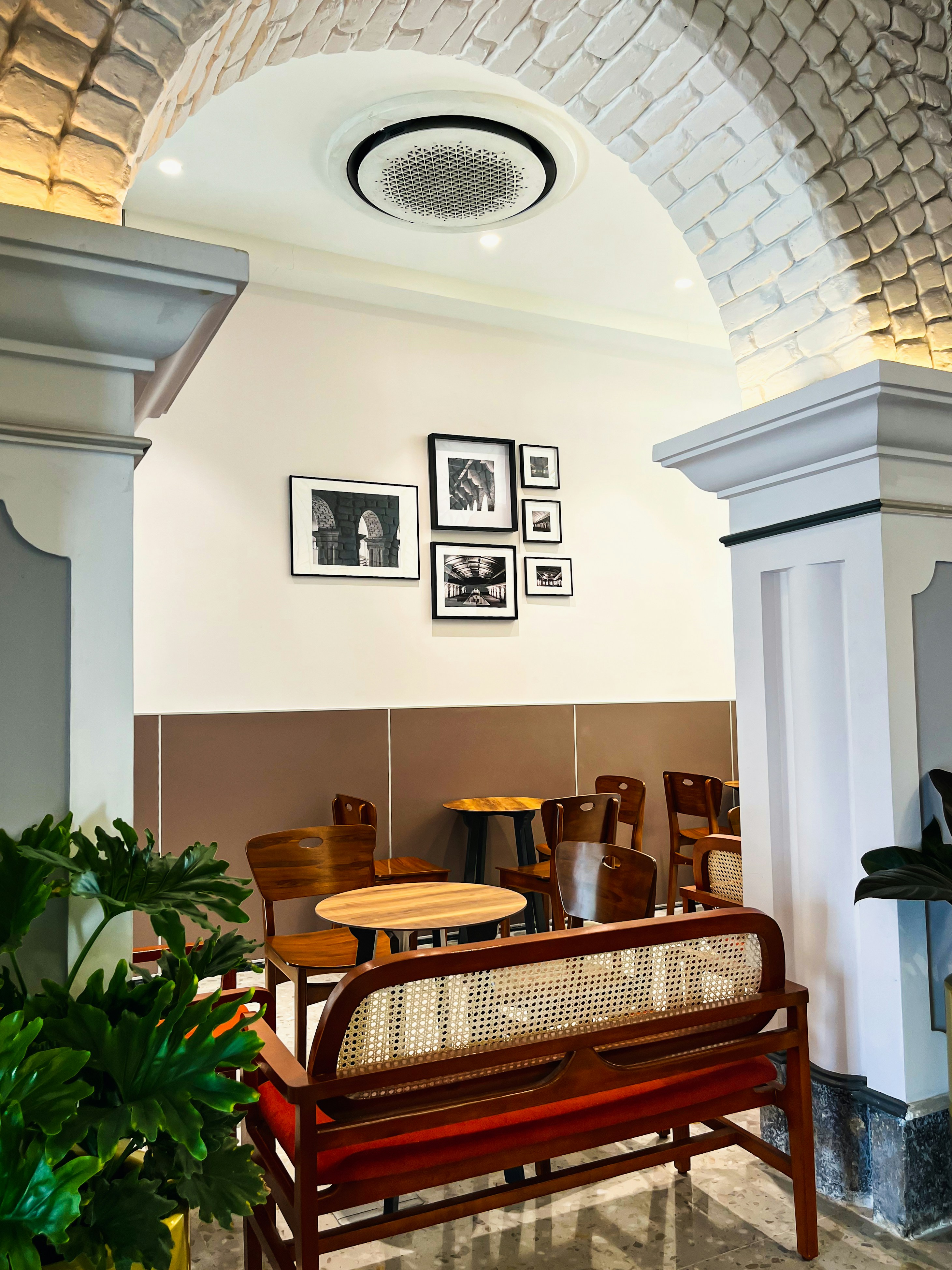 Charming cafe interior featuring a blend of modern and vintage decor, with framed photographs adorning the walls and lush greenery enhancing the ambiance.
