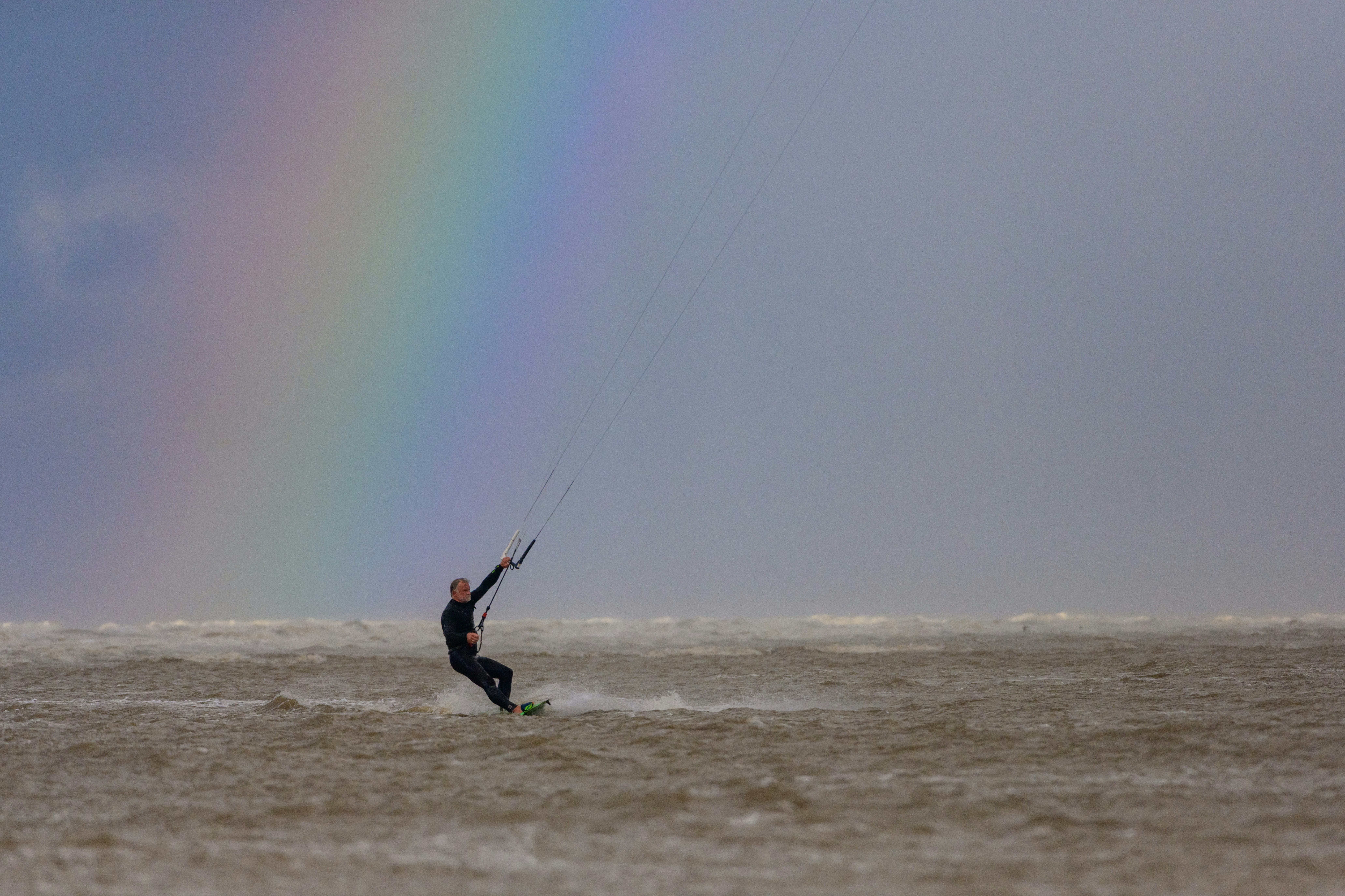 Kite Surfer Beneath a Distant Rainbow