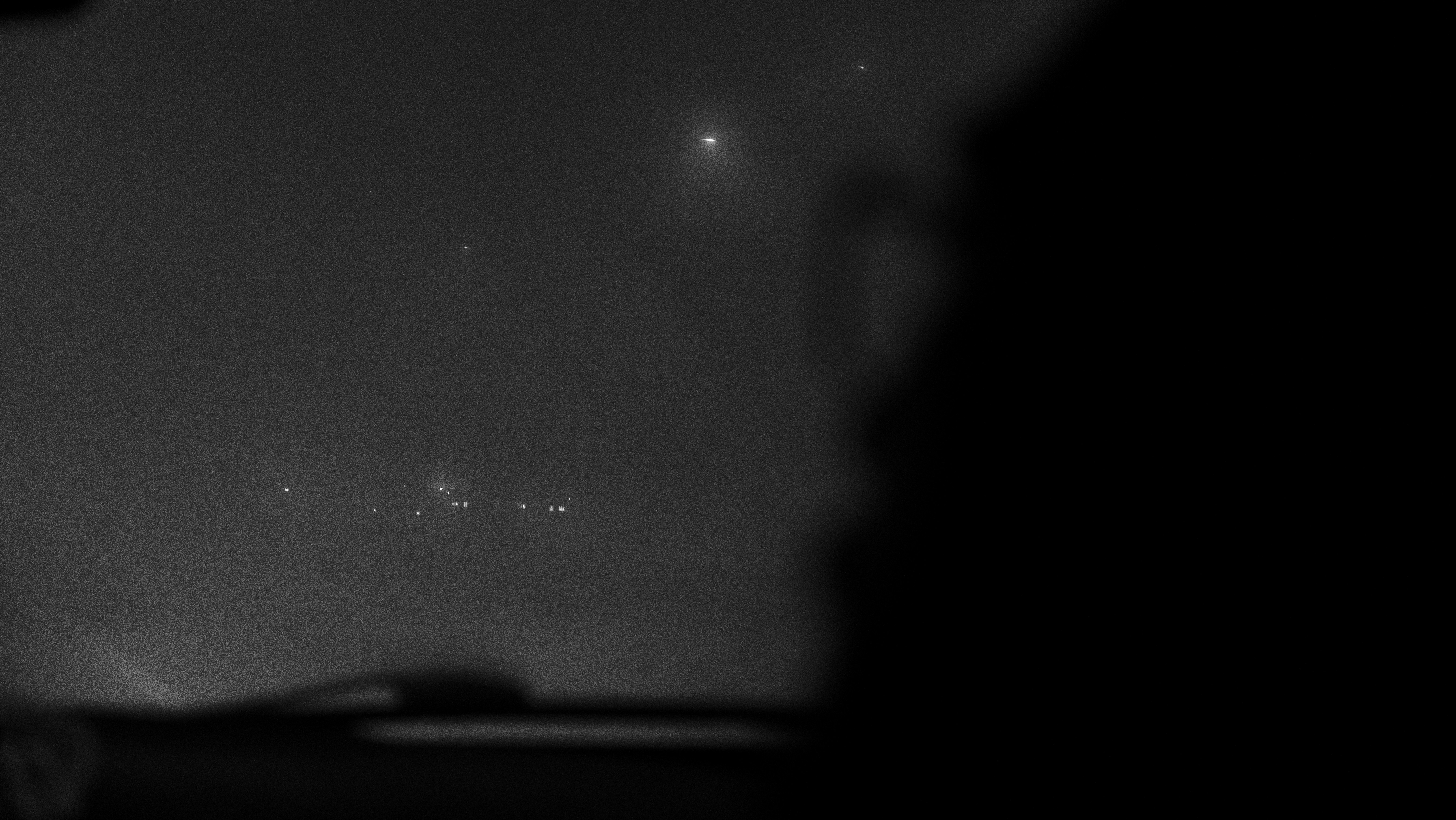 Windshield Night: A Silent Silhouette Beneath Distant Lights